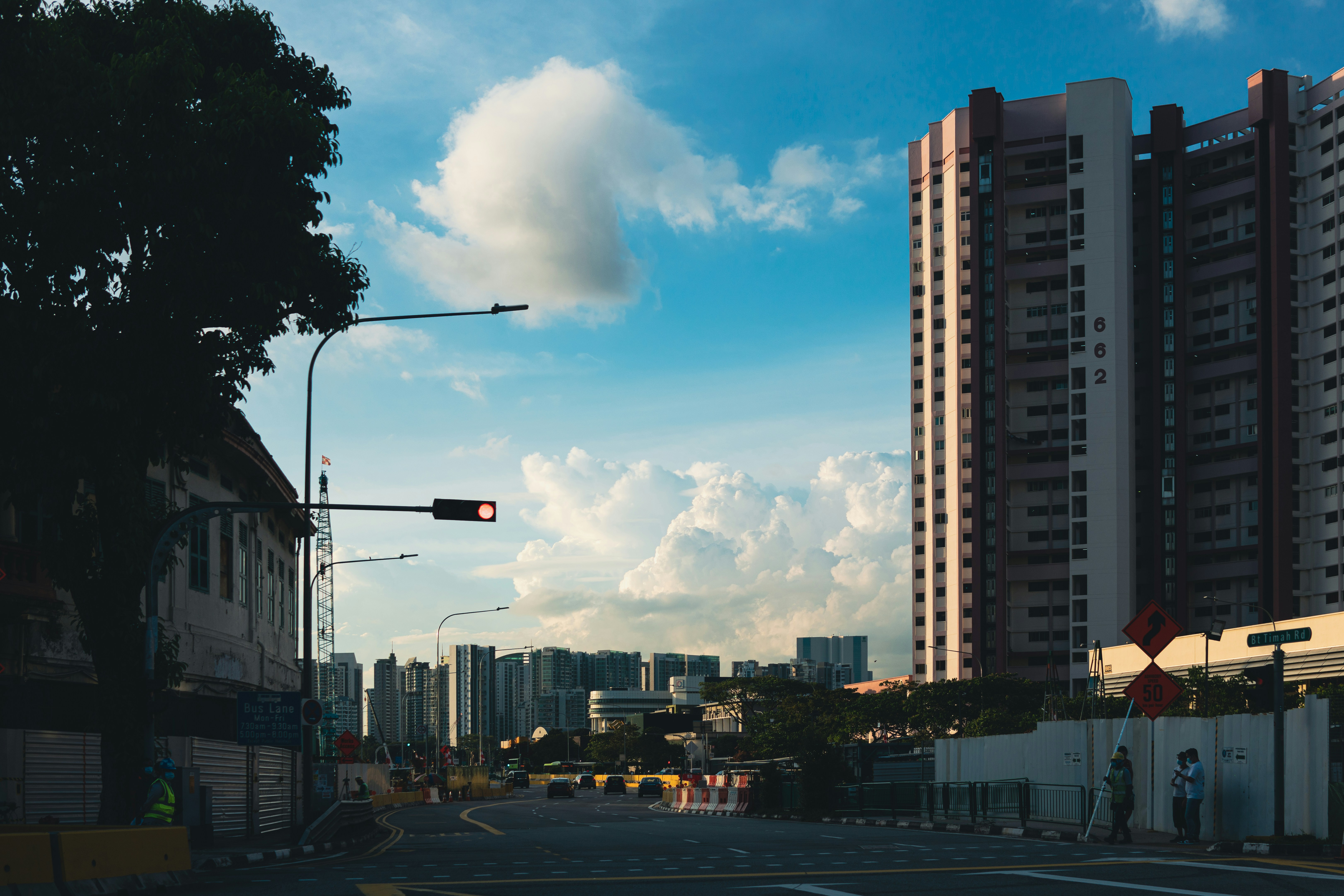 A city street scene featuring a traffic light and modern buildings under a dynamic sky filled with clouds.