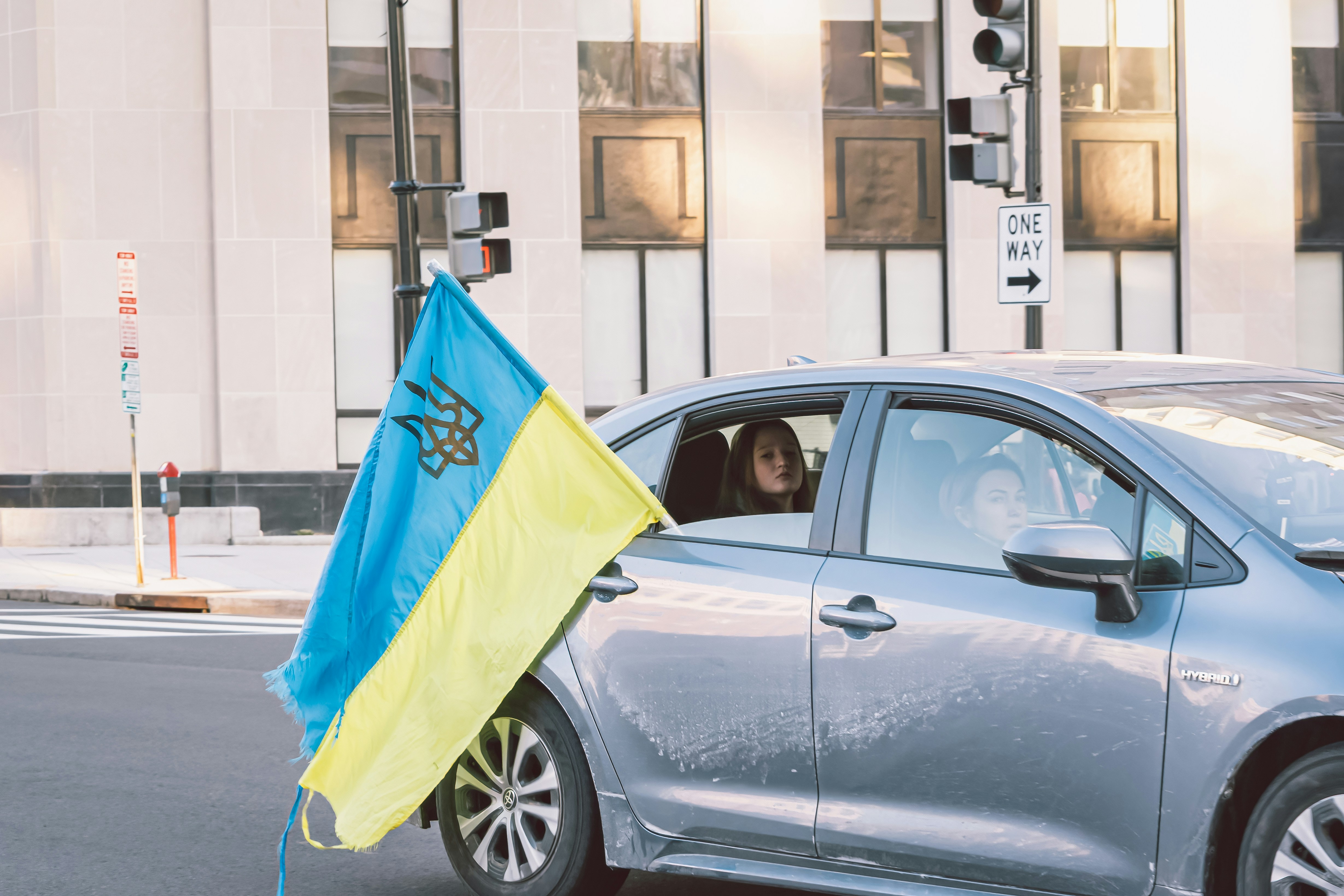 Car with Ukrainian flag waving from the window, capturing a moment of cultural pride during a city drive.