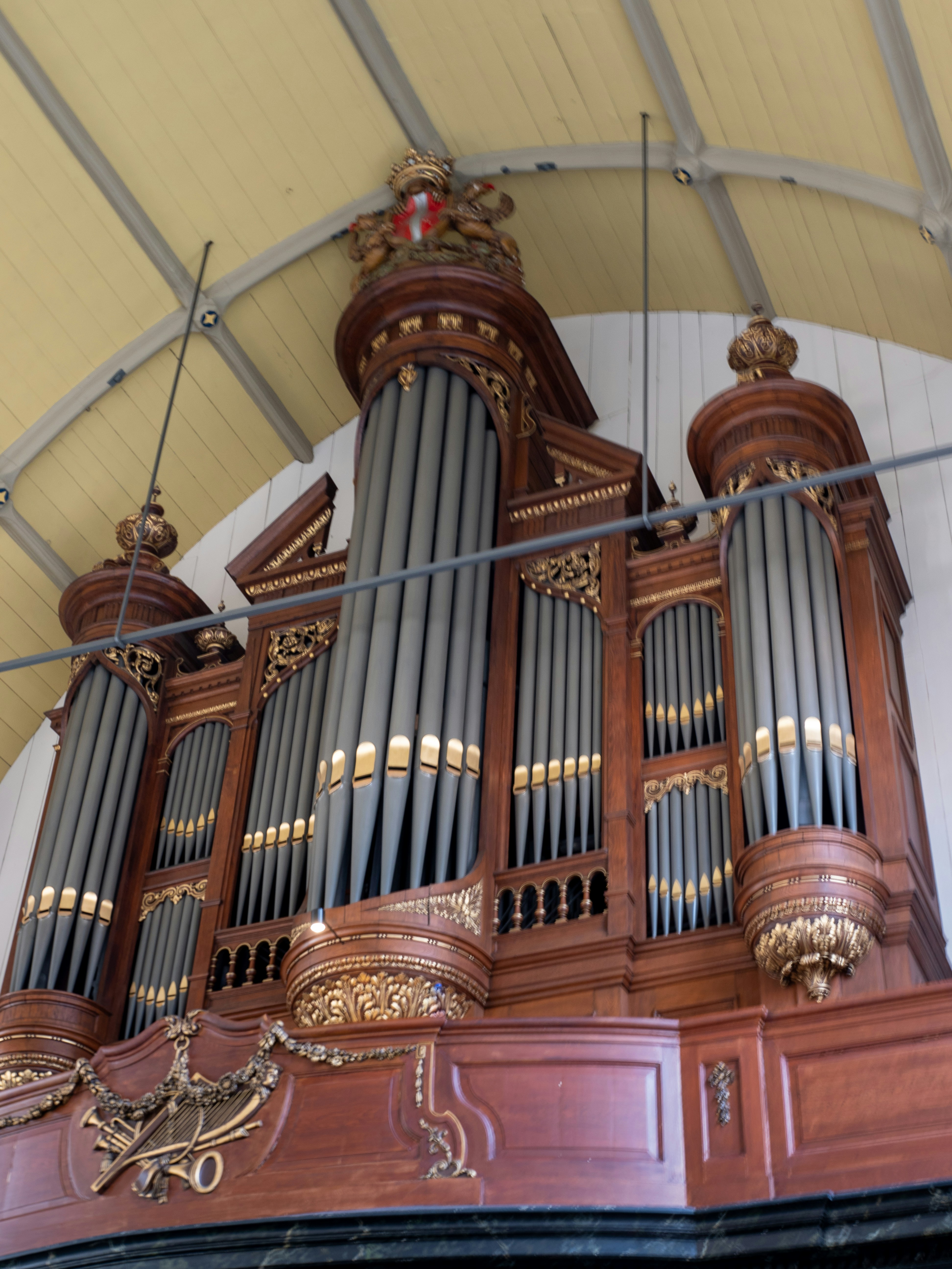Intricate wooden organ with ornate details and pipes, set against a simple backdrop. A testament to craftsmanship and musical heritage.