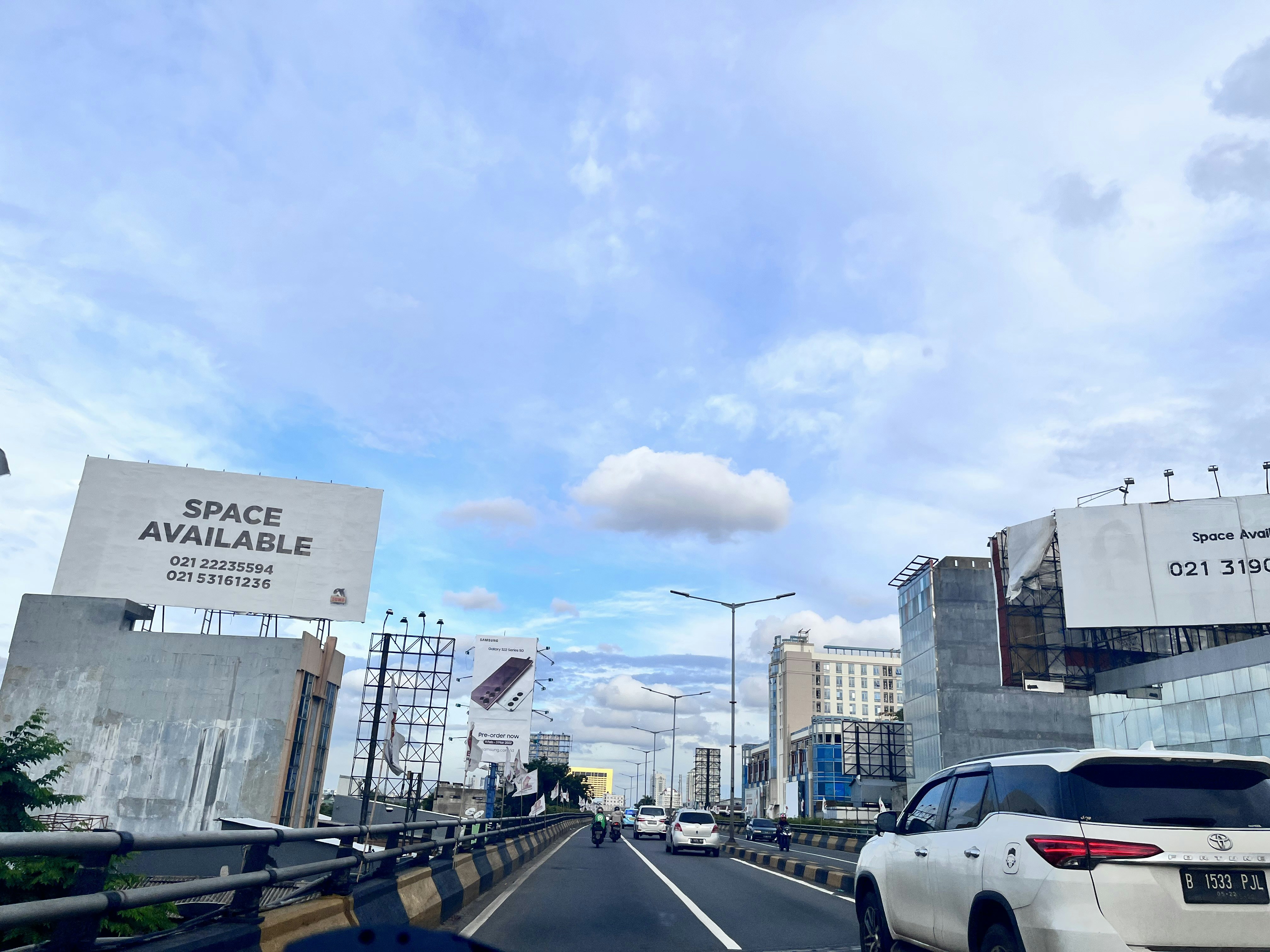 a white car driving down a street next to tall buildings