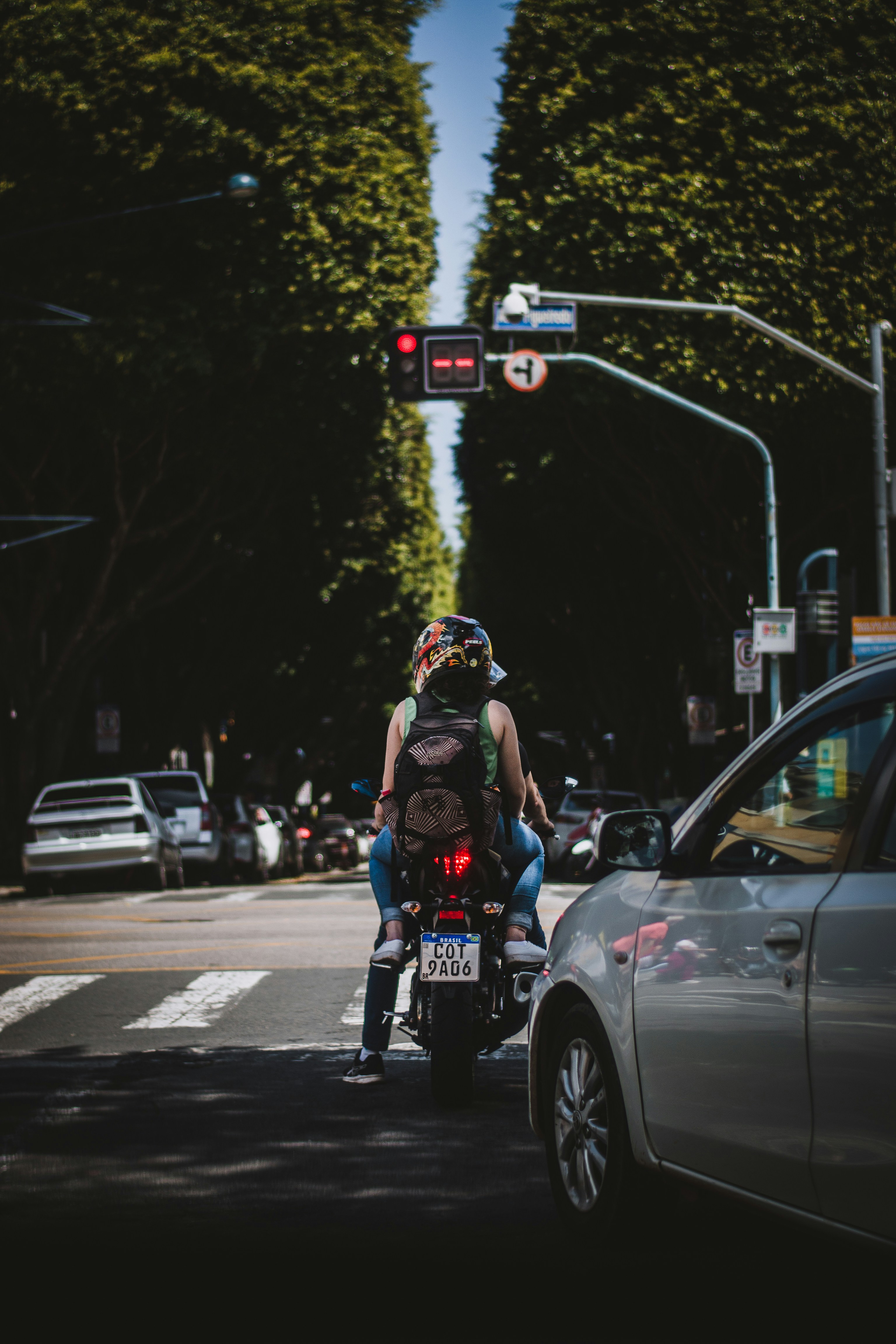 A man riding a motorcycle down a street next to a traffic light photo ...