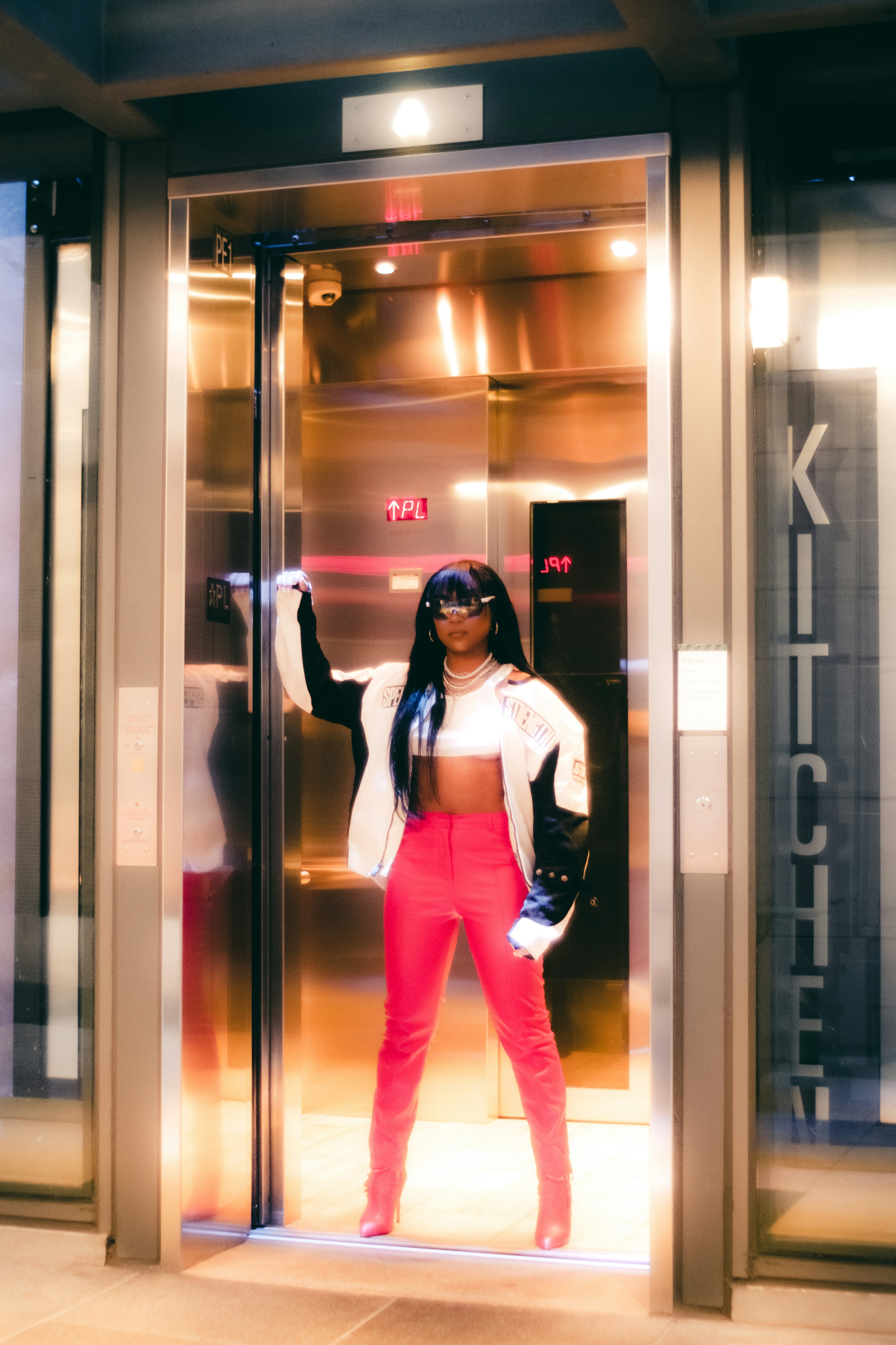 A woman standing in an elevator wearing pink pants photo – Free ...