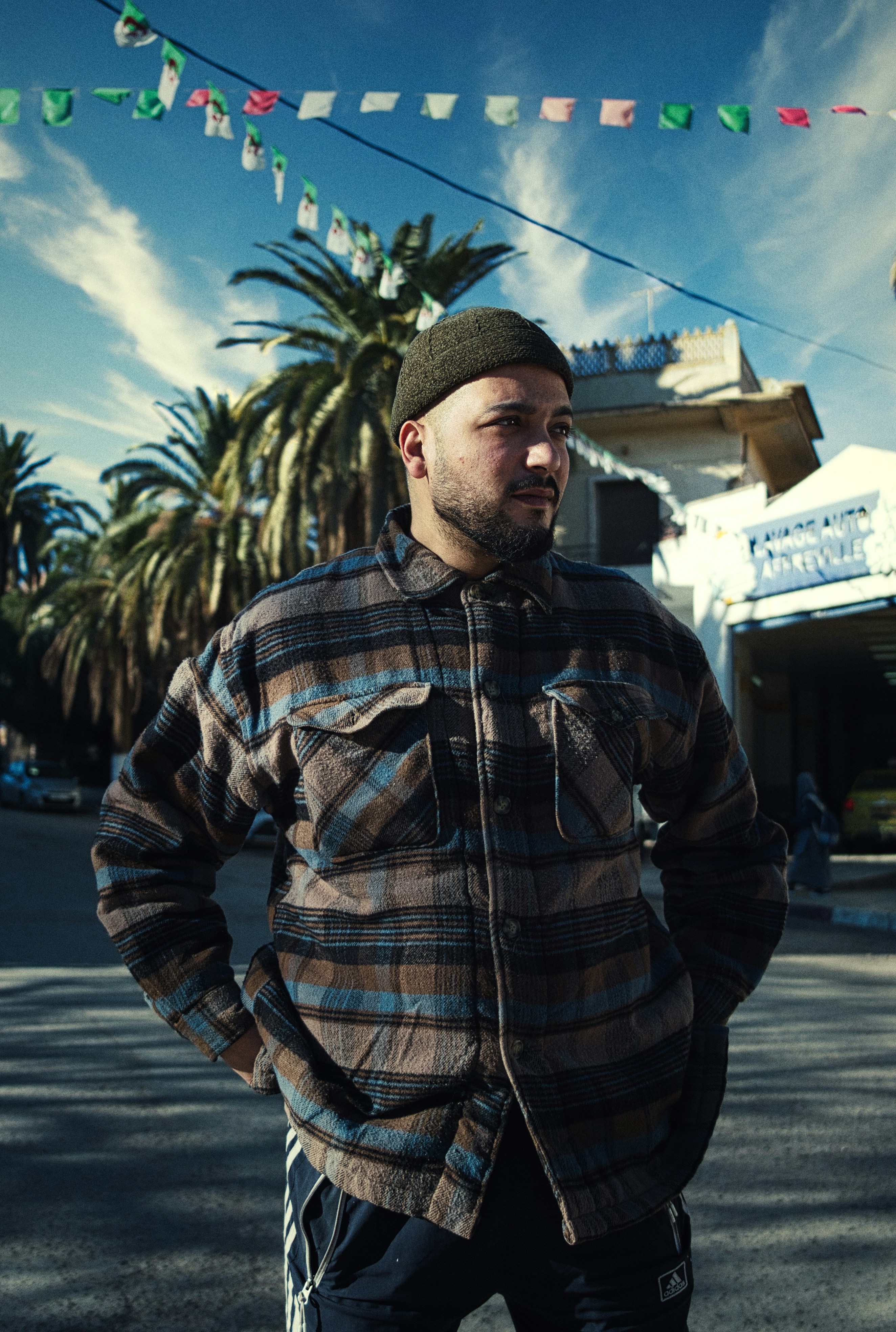 Portrait in the Coastal Street: A man in a plaid jacket stands beneath festive bunting