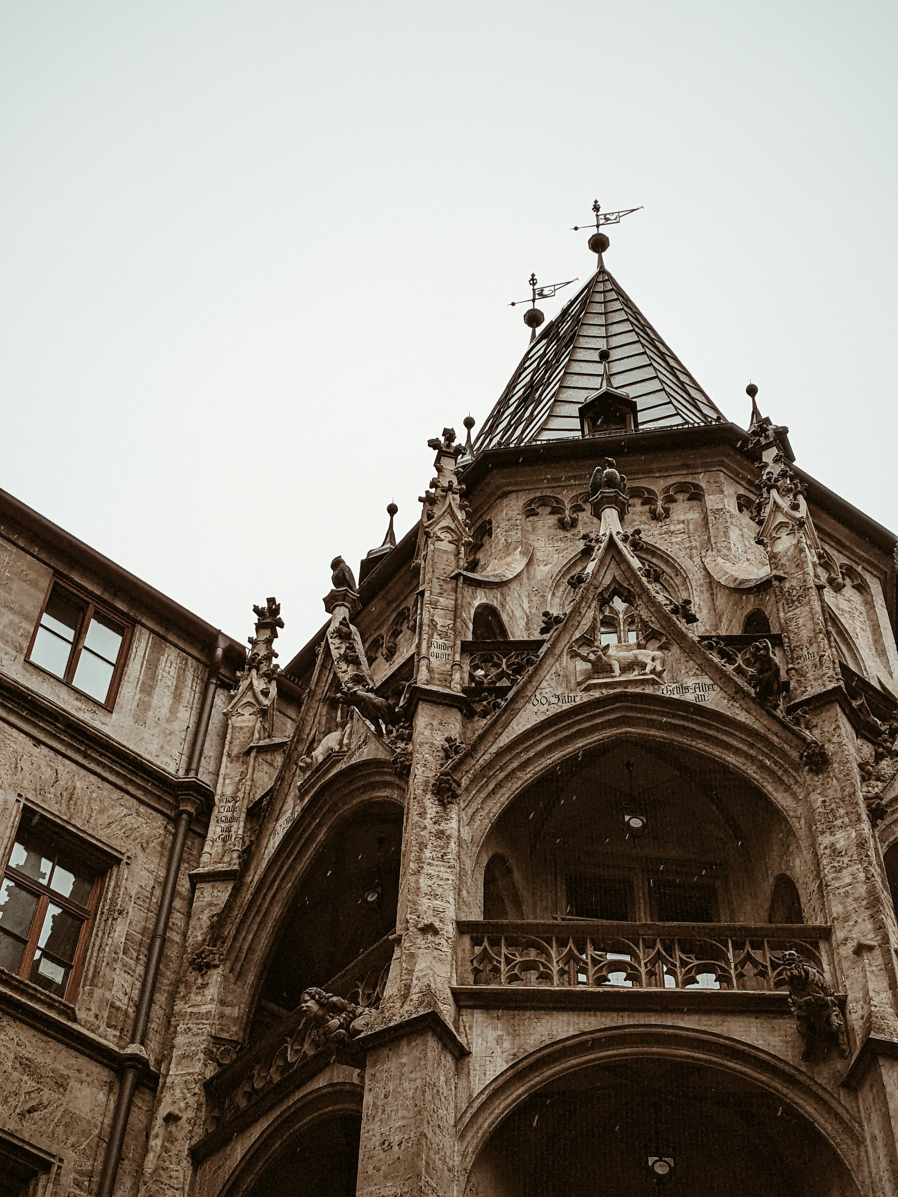 Stone gothic archway and spire with intricate carvings and statues, captured from a low angle to emphasize architectural detail and verticality.