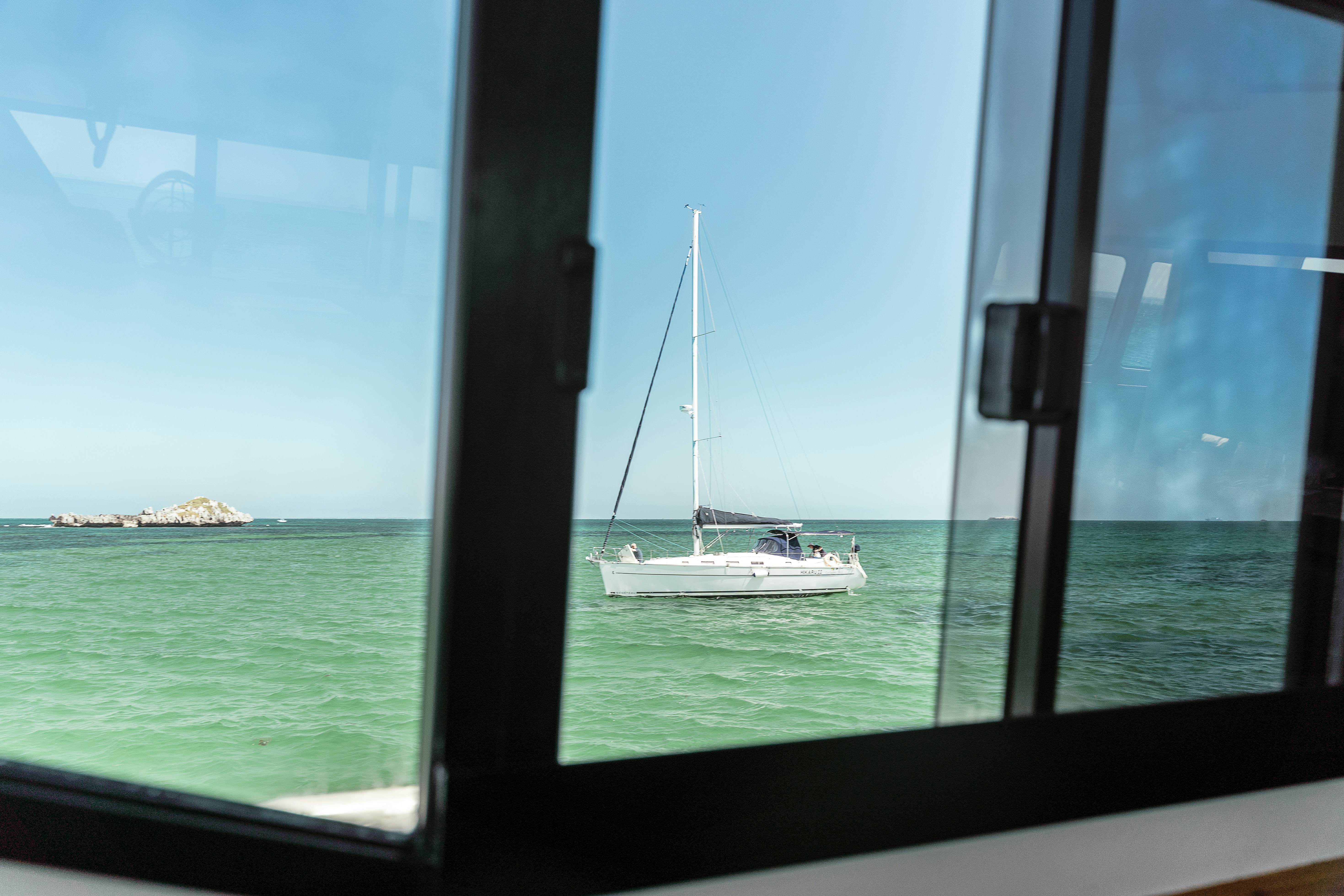 Trimmed Horizon Through a Window Frame: Sailboat in Emerald Waters