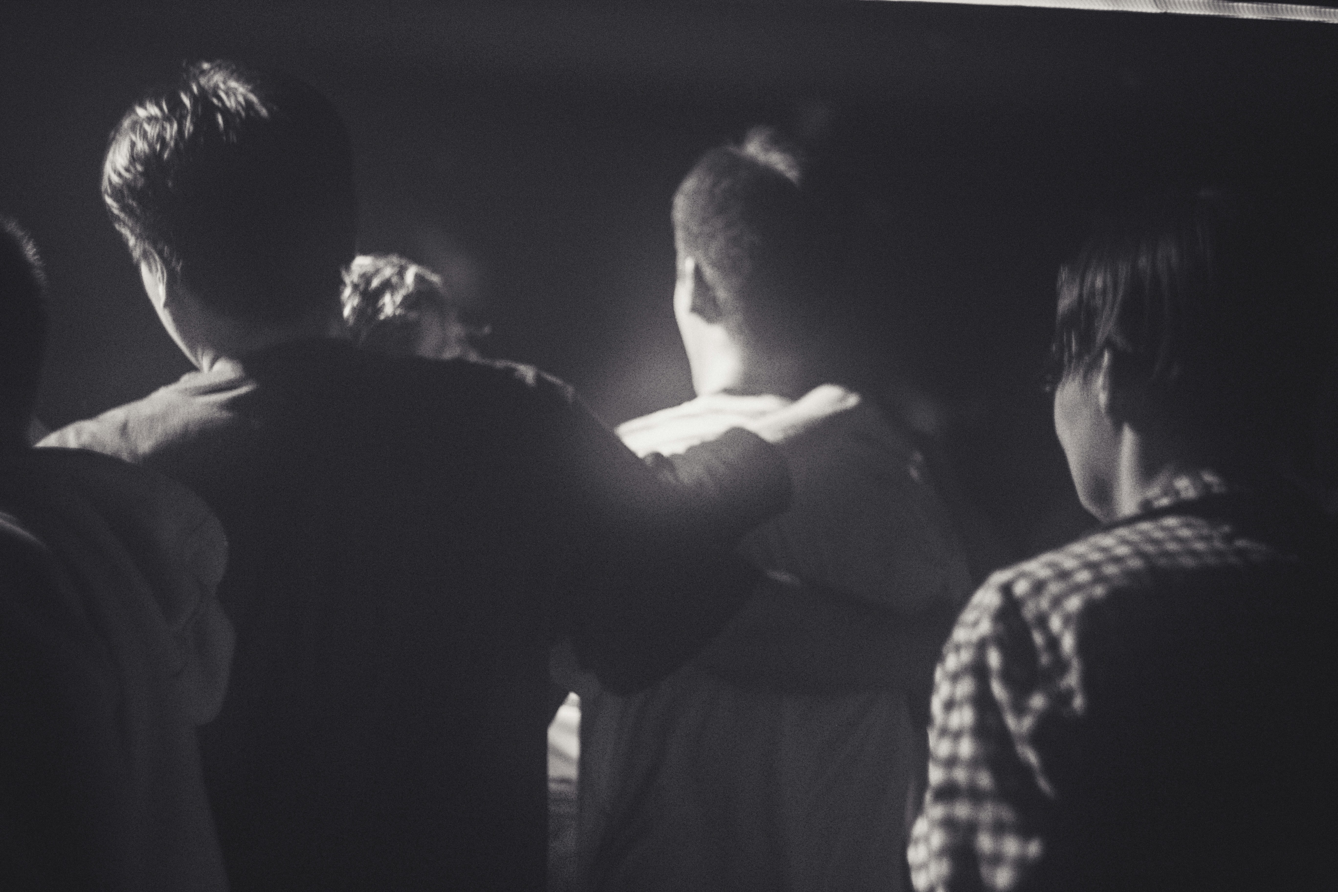 Group of individuals sharing a moment in low light, emphasizing camaraderie and intimacy.