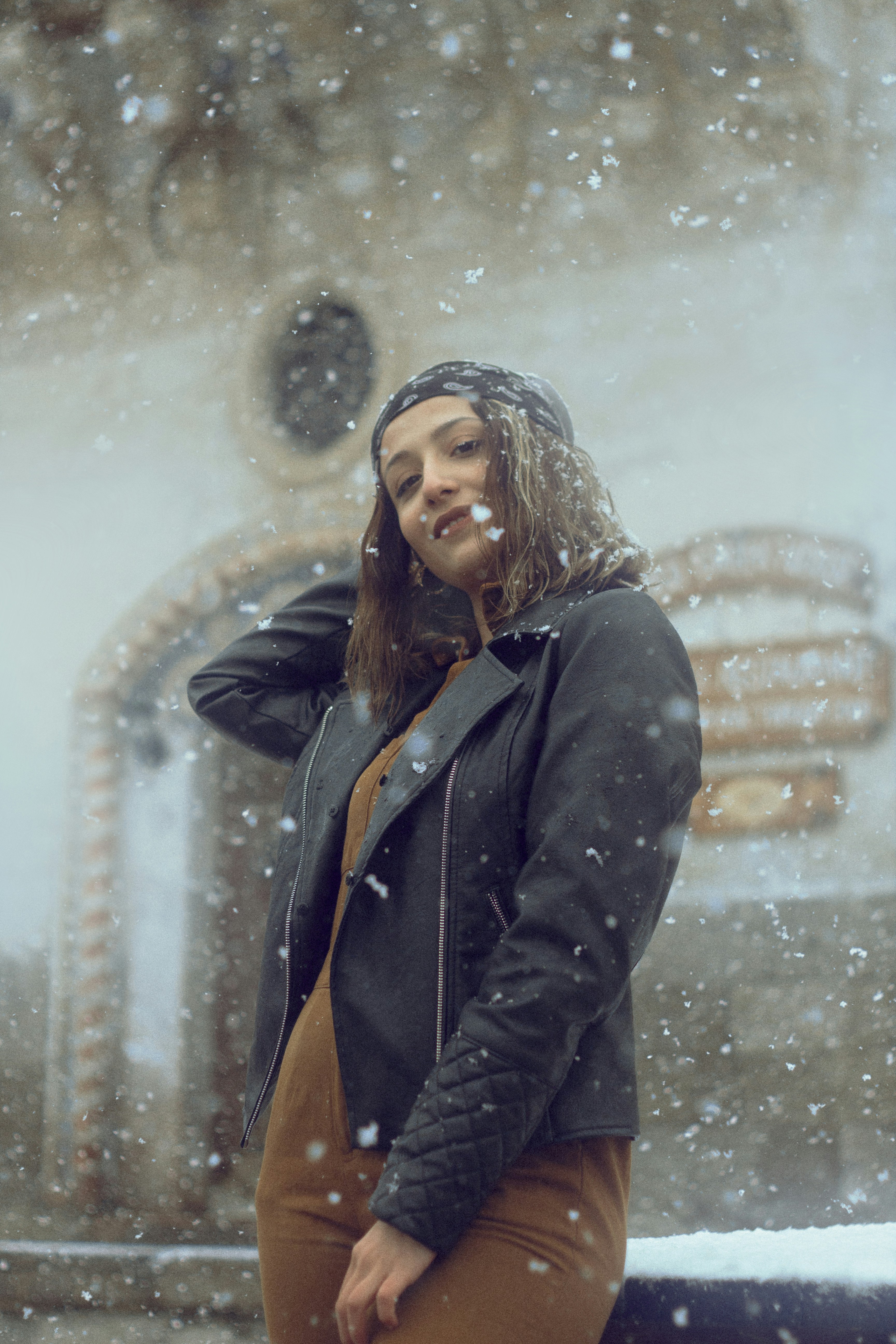 Portrait Beneath Falling Snow at a Weathered Archway