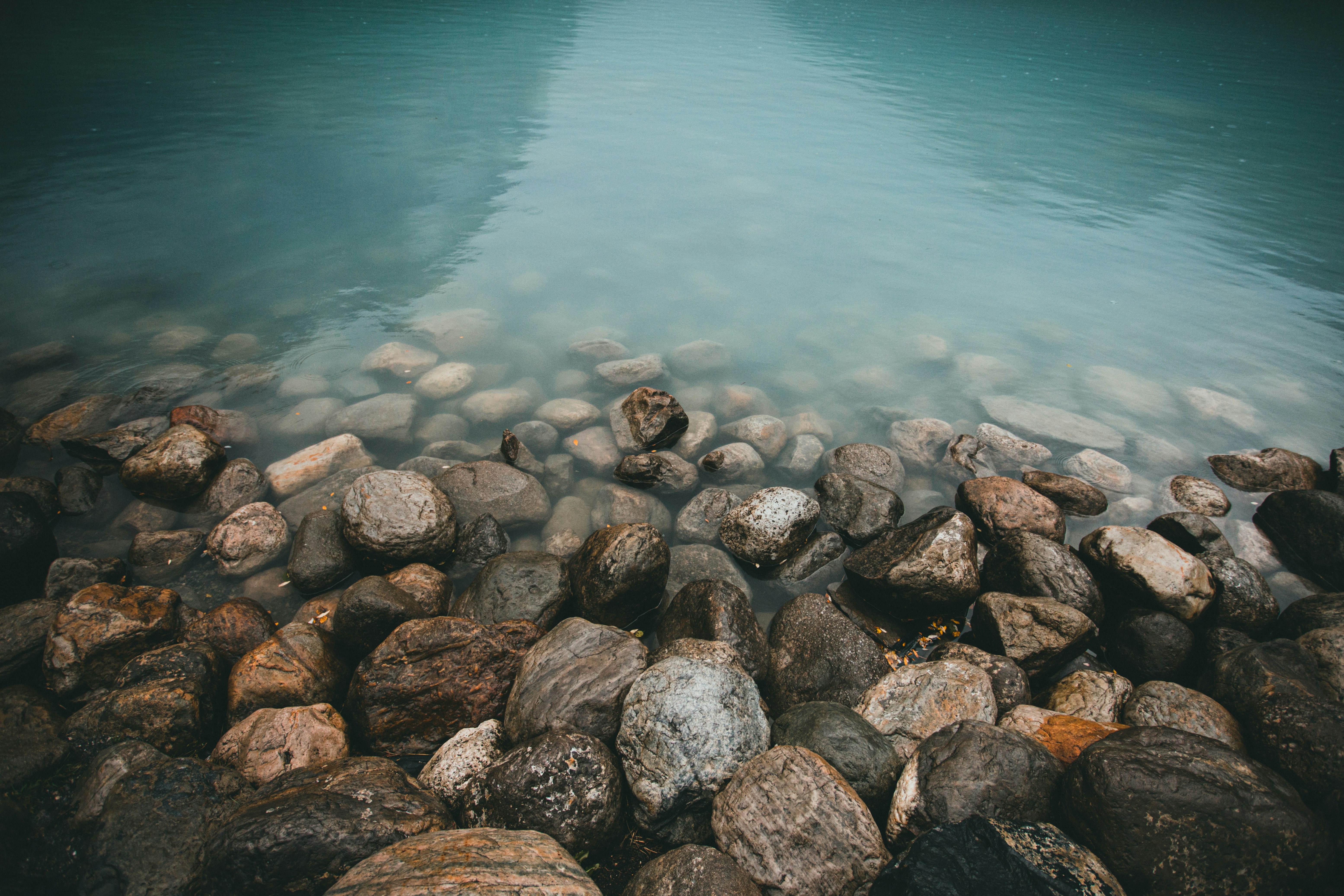 A body of water surrounded by rocks and rocks photo – Free Grey Image ...
