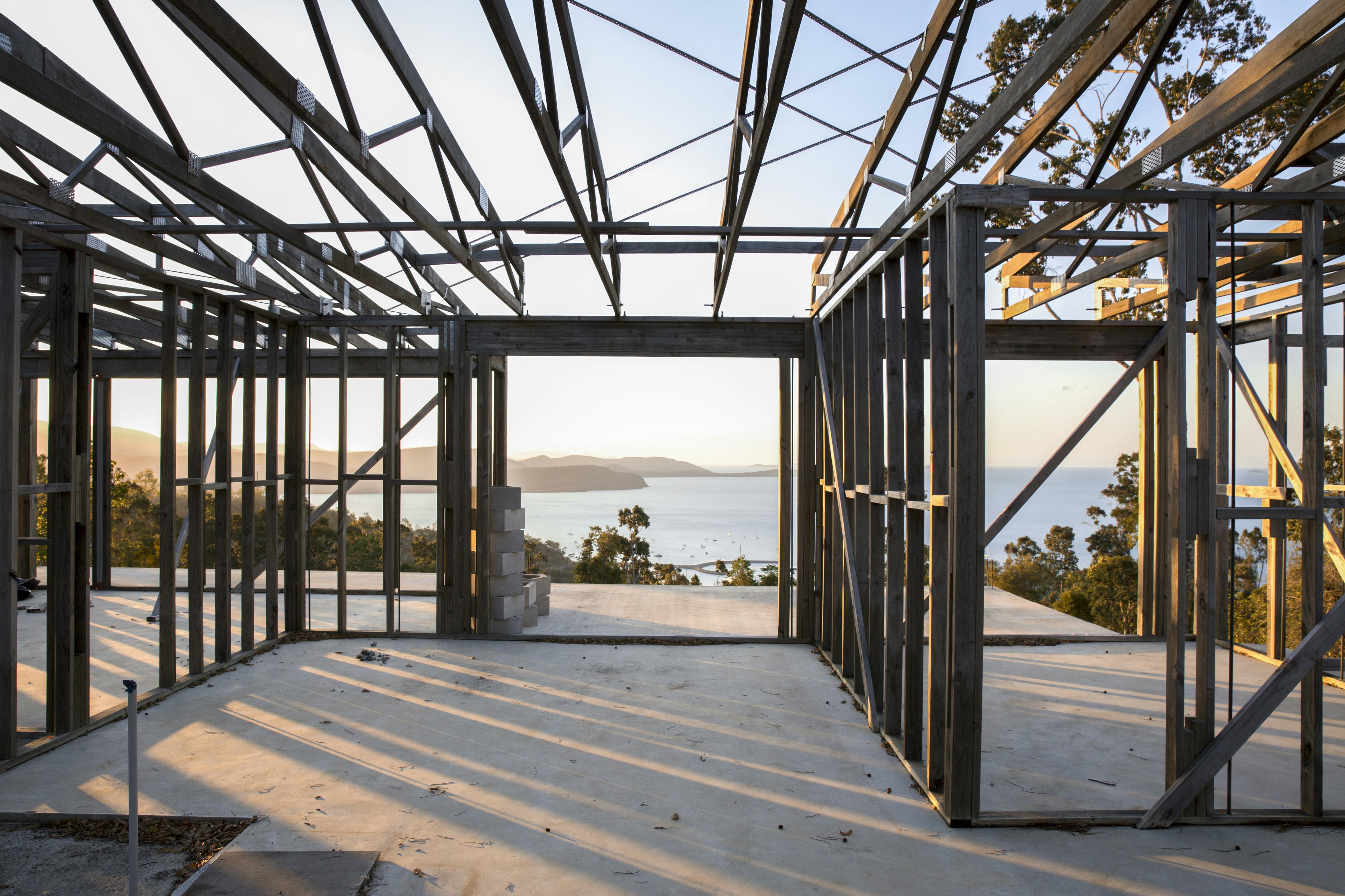 Golden Hour Through a Half-Constructed Frame: Seaside Vista Beyond the Timber Skeleton