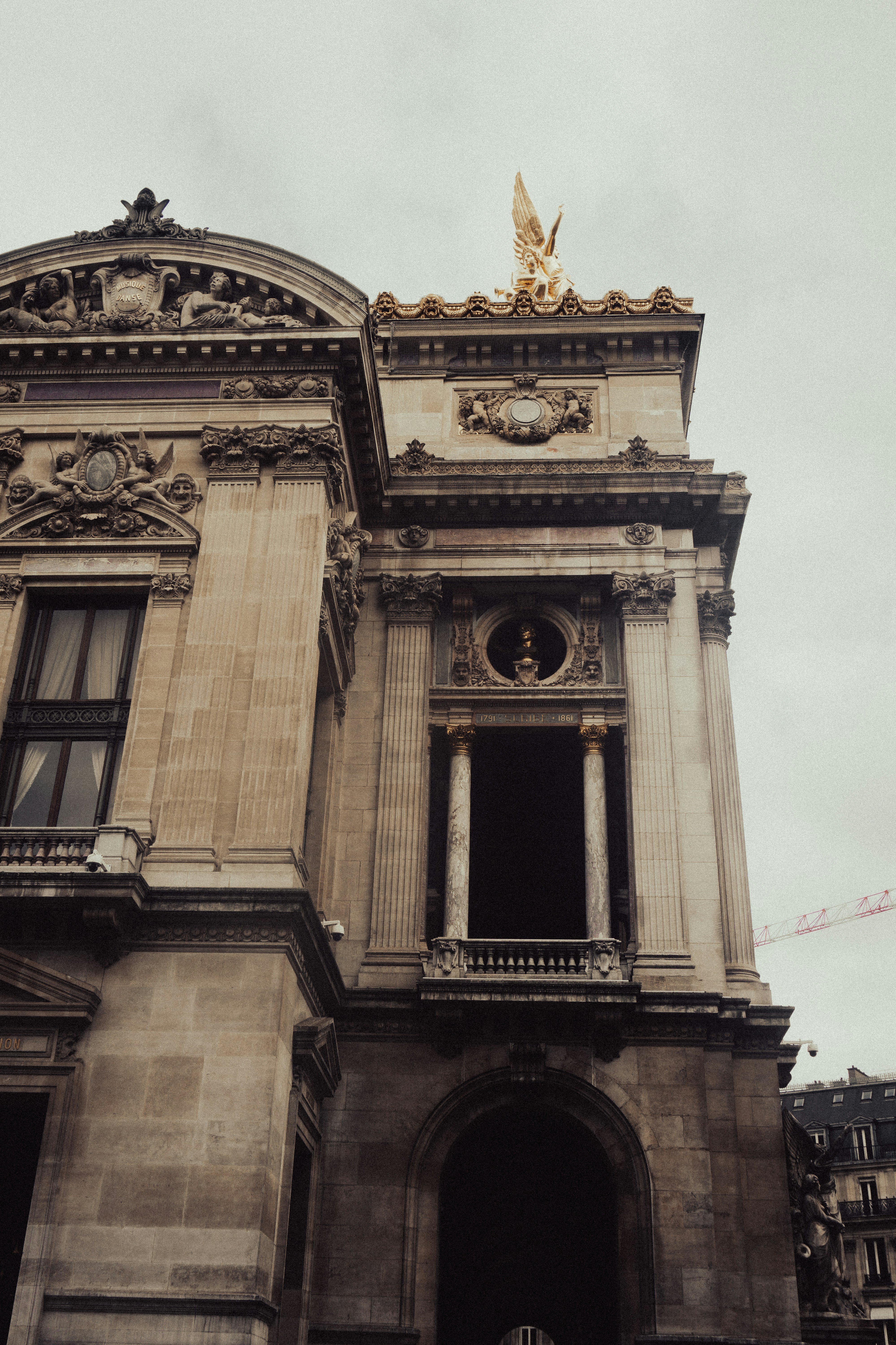 Winged Apex over Stone Carvings: A Low-Angle Study of a Historic Facade