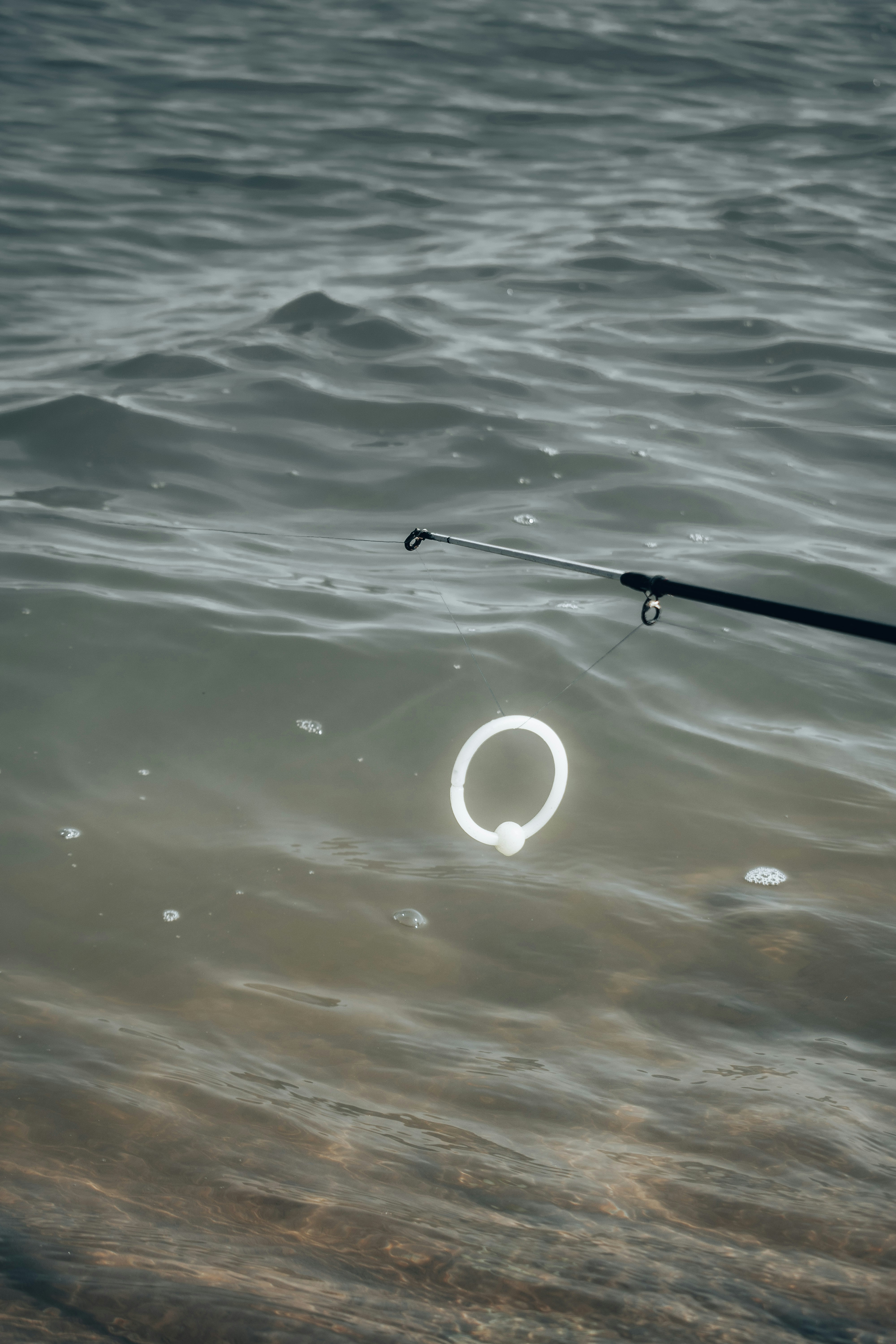 A fishing rod in the middle of a body of water photo – Free Grey Image ...