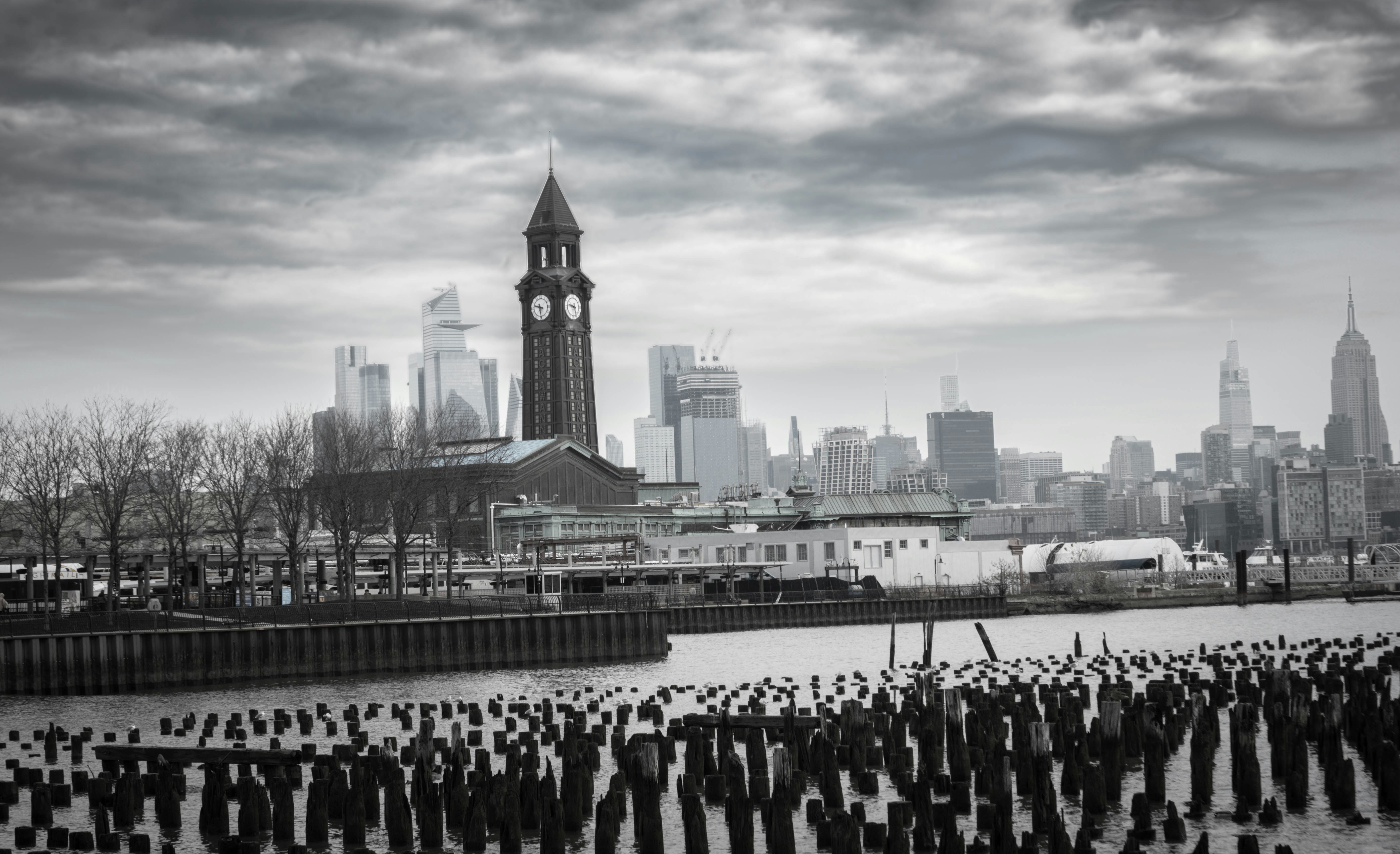 Black and white cityscape featuring a prominent clock tower under a cloudy sky.