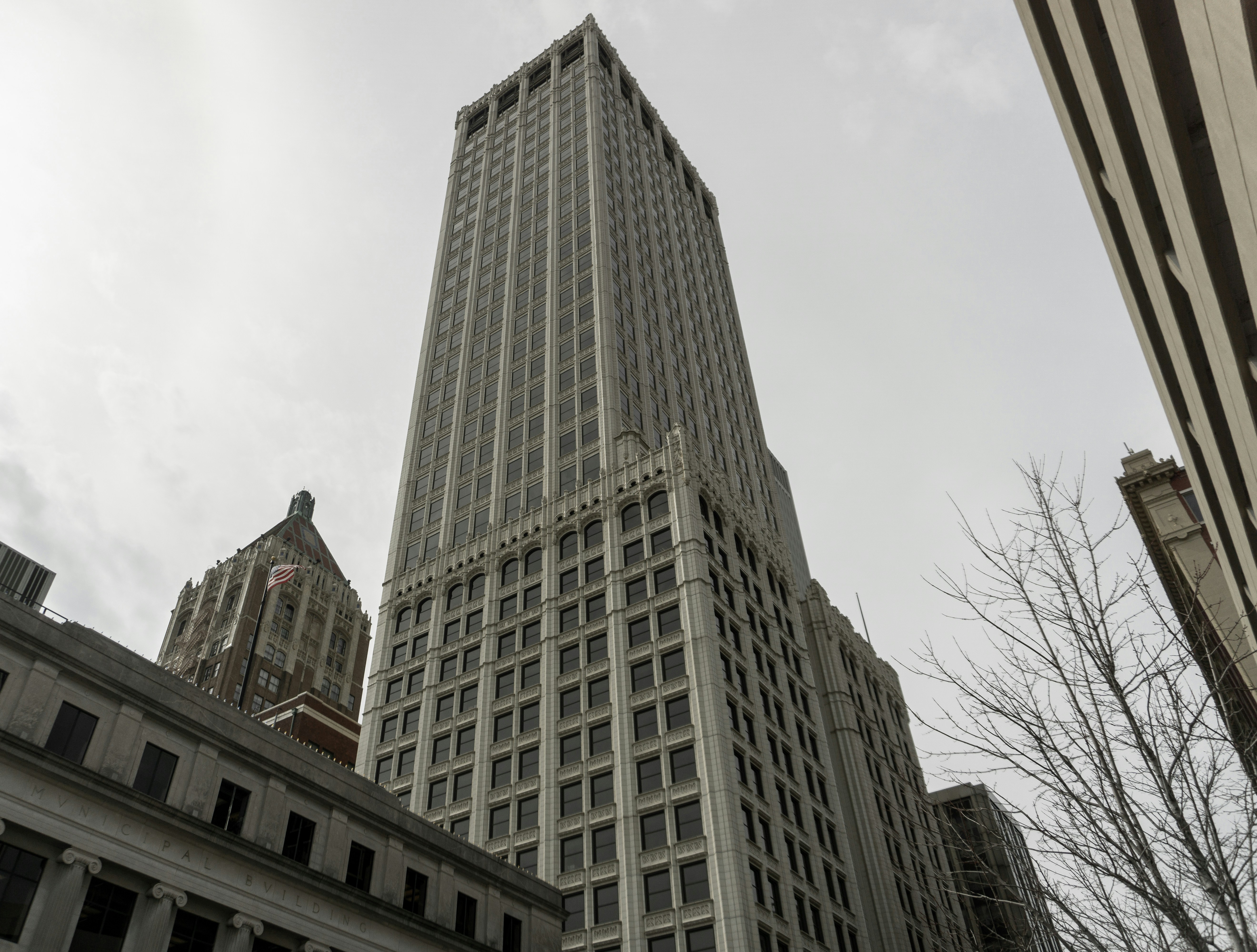 Tall skyscraper dominating the city skyline under a cloudy sky.