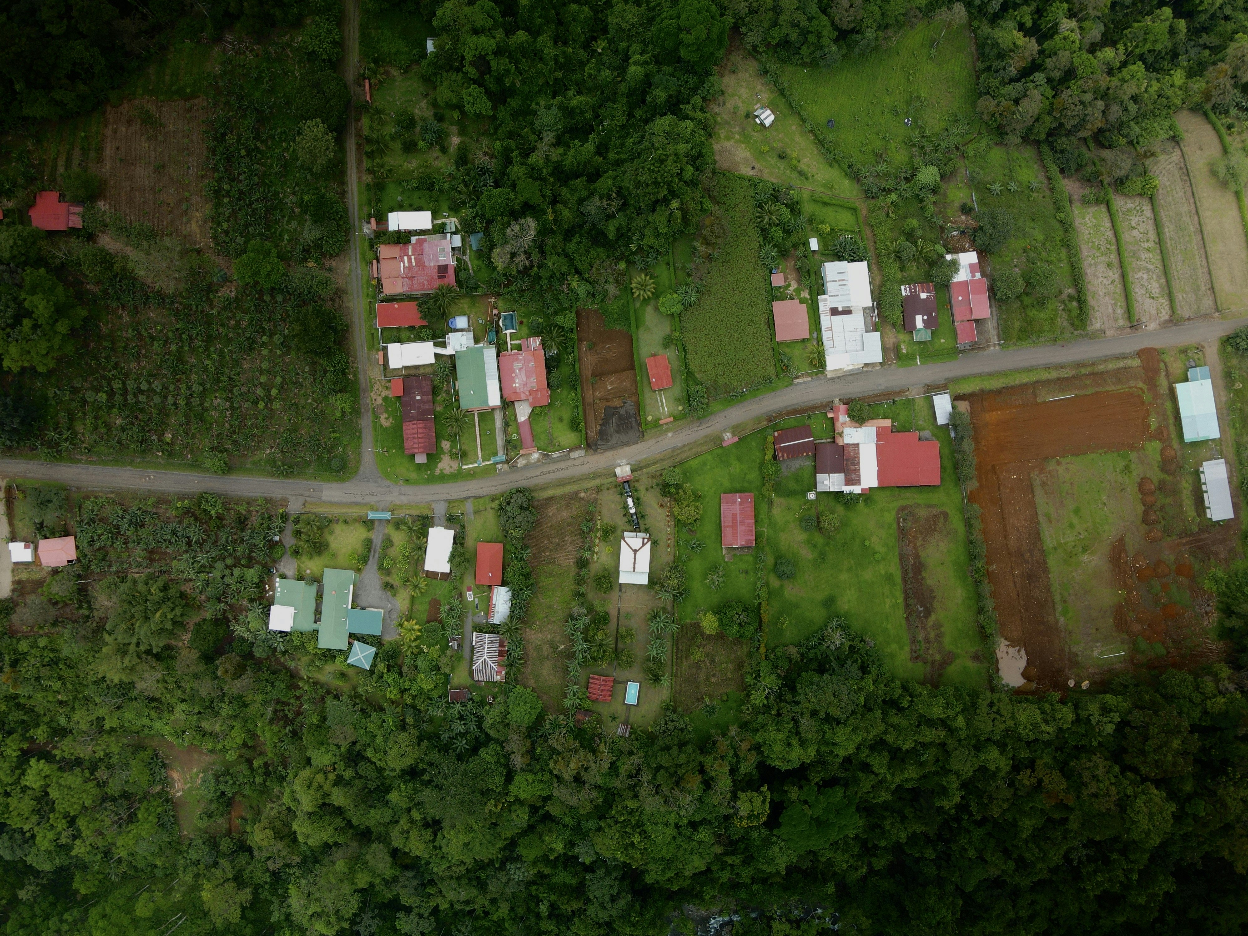 Aerial view of a small village with colorful rooftops surrounded by lush greenery and fields.