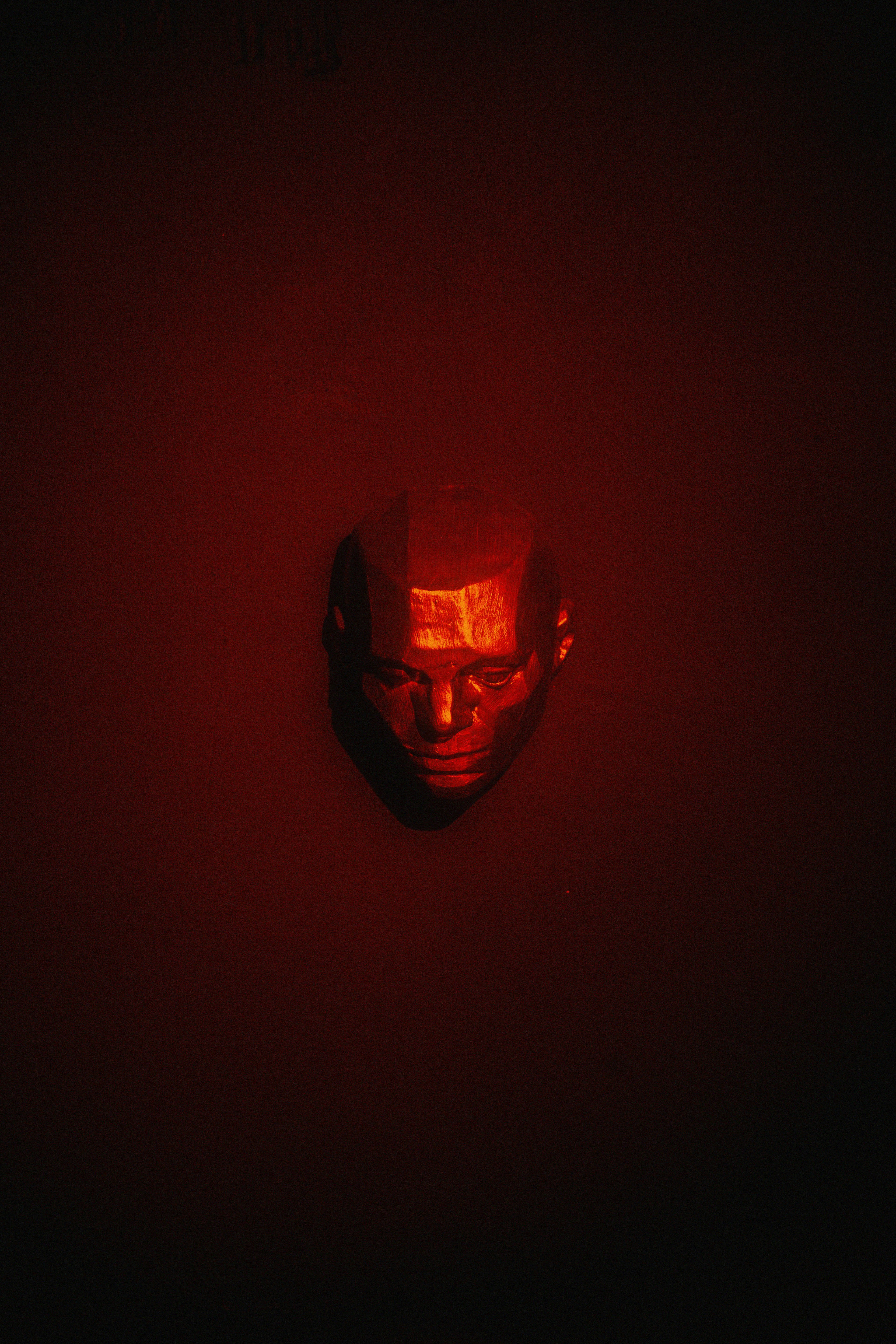 Redlit Mask: Central Head in a Dark Embrace