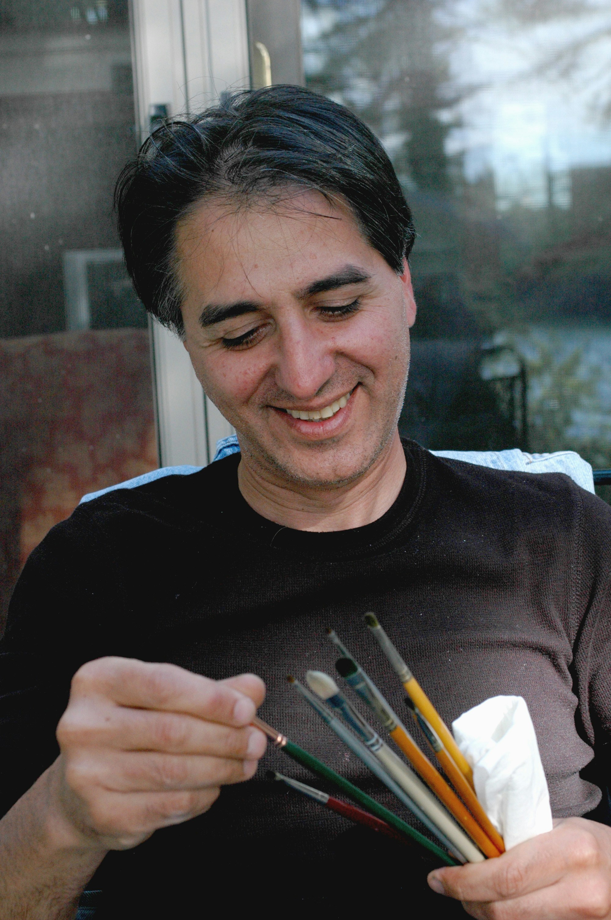 Artist examining a collection of paintbrushes, showcasing a moment of inspiration and creativity.