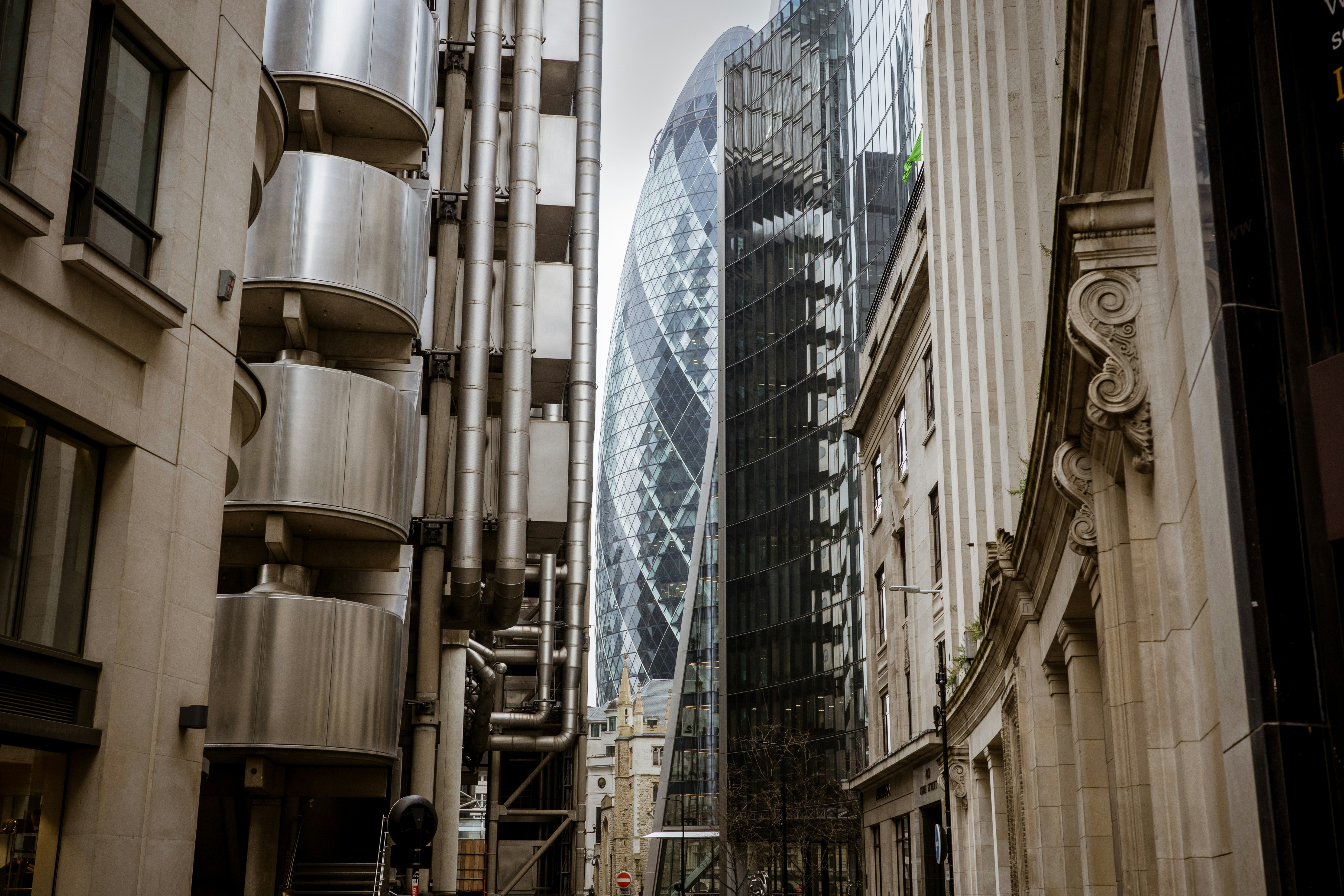 Modern skyscrapers juxtaposed against classic buildings in a narrow city alleyway, showcasing architectural diversity.