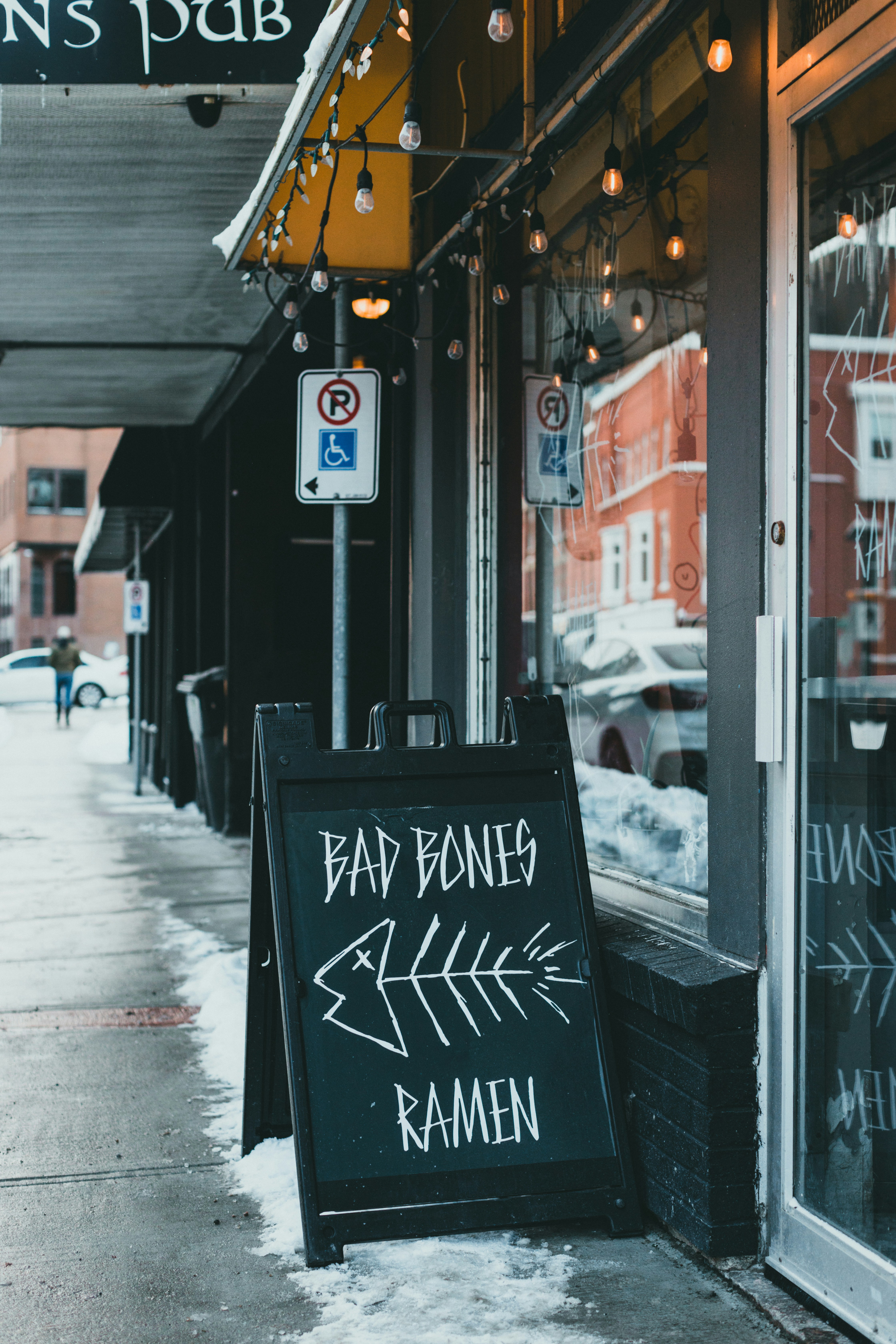 Dark Signboard on Snowy Sidewalk signaling a ramen joint