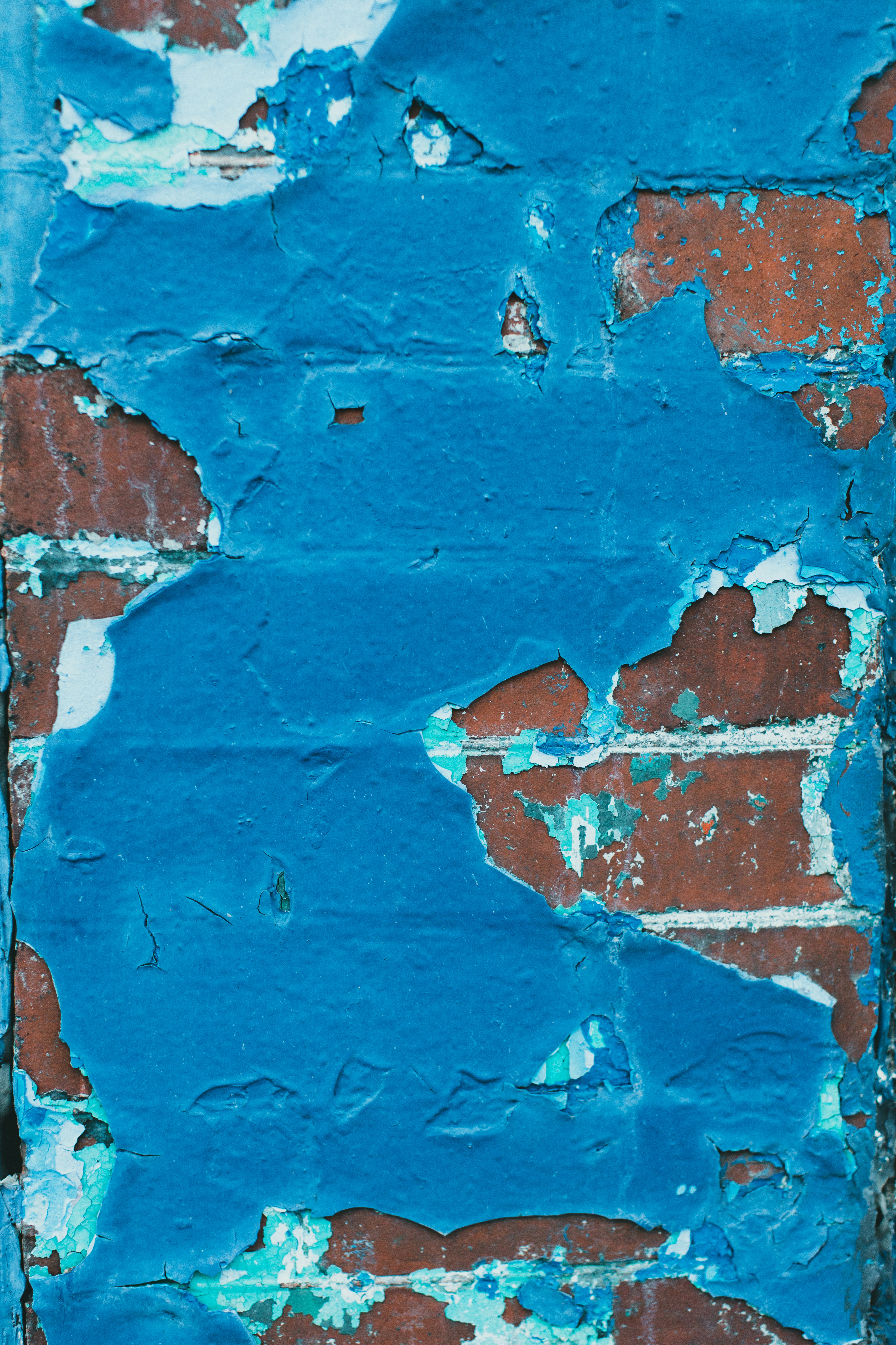 a red and blue brick wall with peeling paint