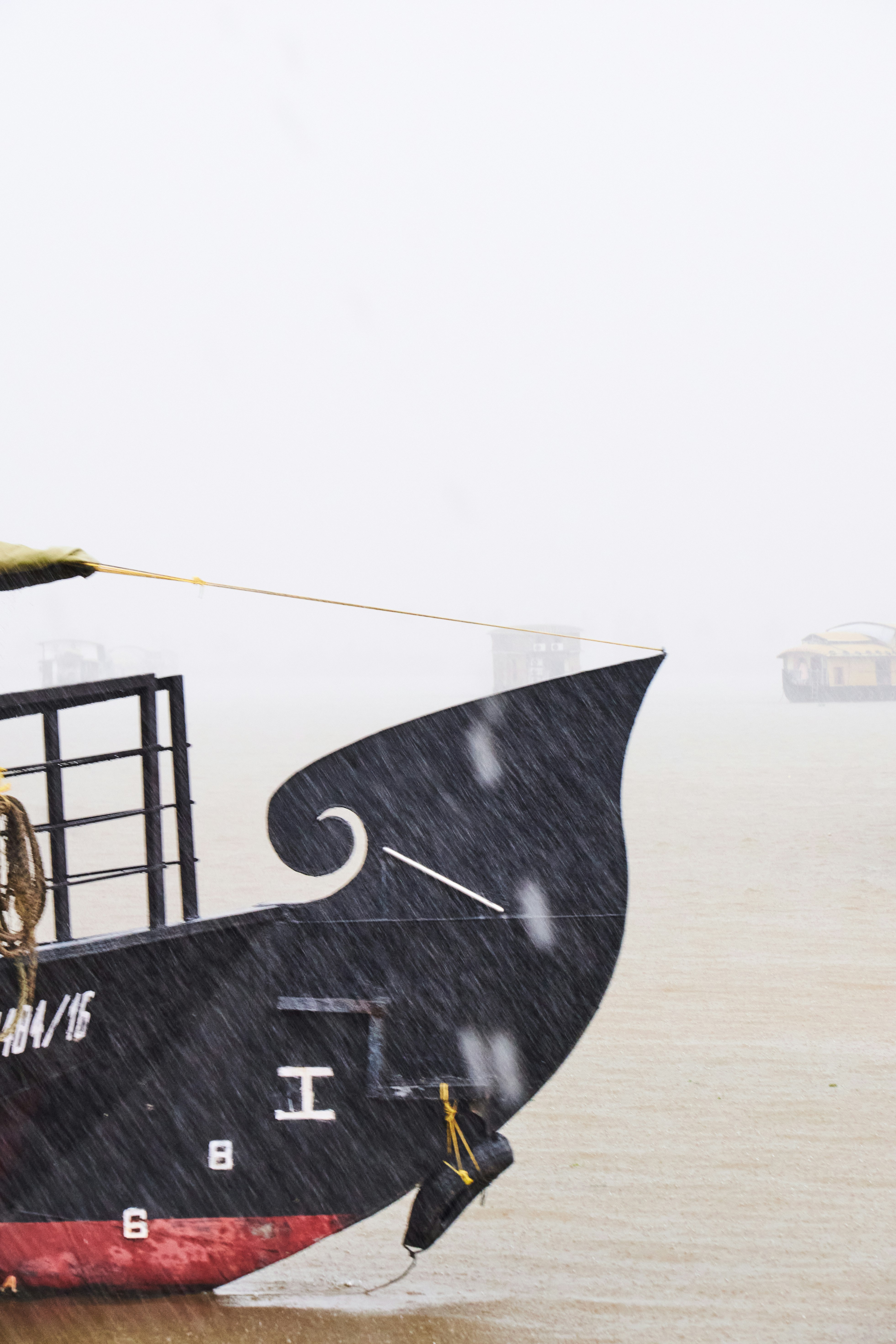Noir Bow in the Mist: a Curved Hull Reaching into a Rainy Harbor