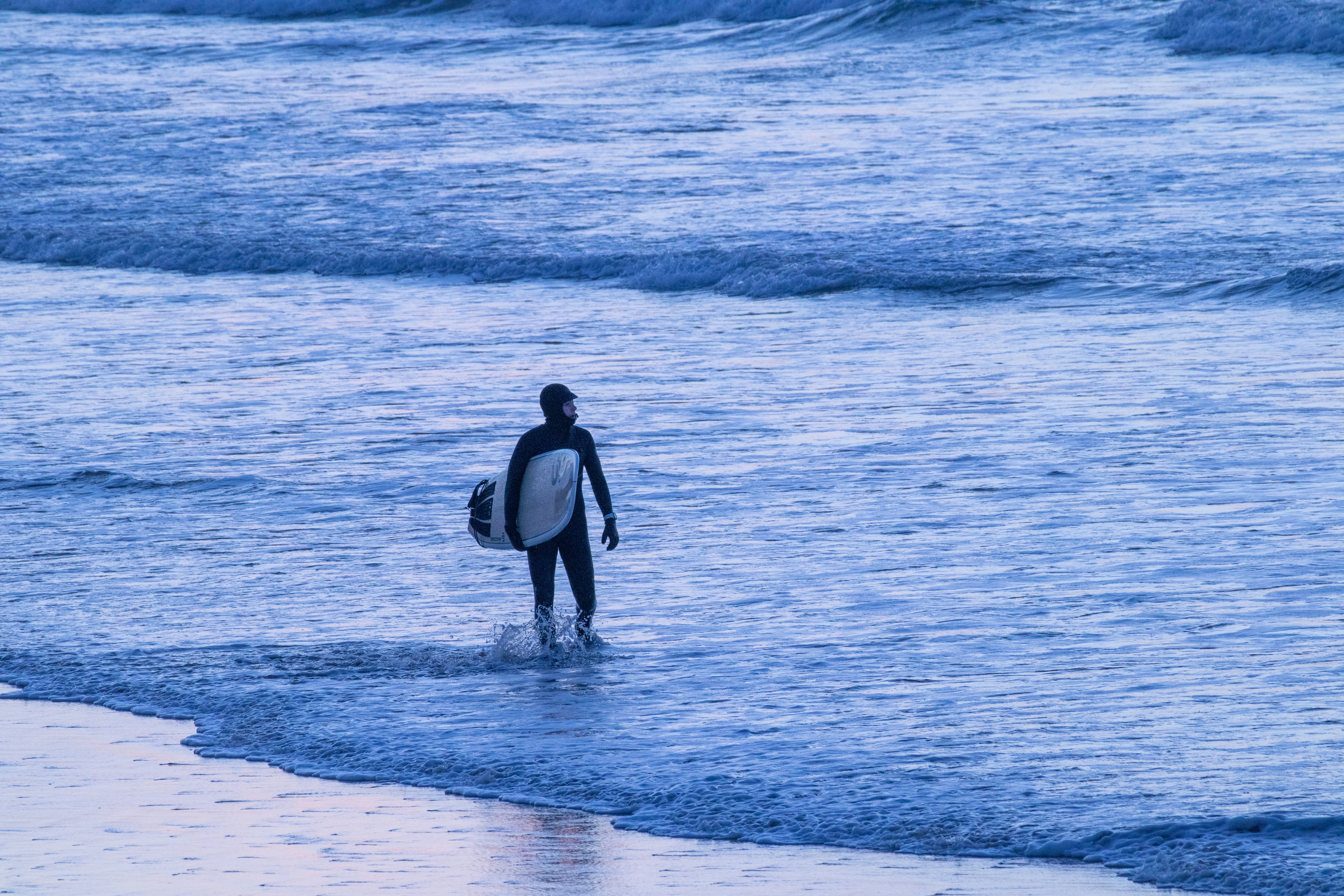 A person walking out of the ocean with a surfboard photo – Free Beach ...