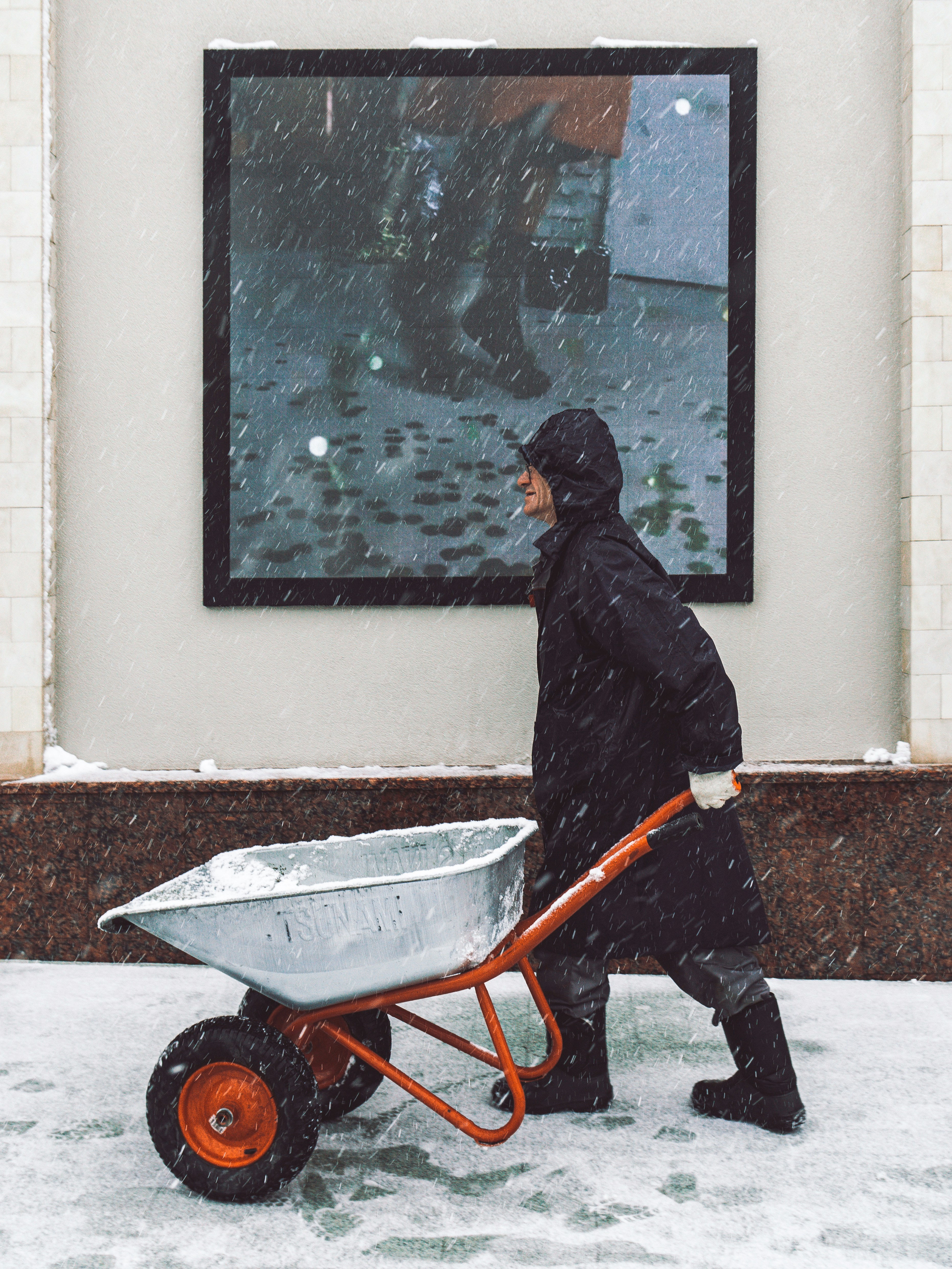 A man pushing a wheelbarrow in the snow photo – Free Street photography ...