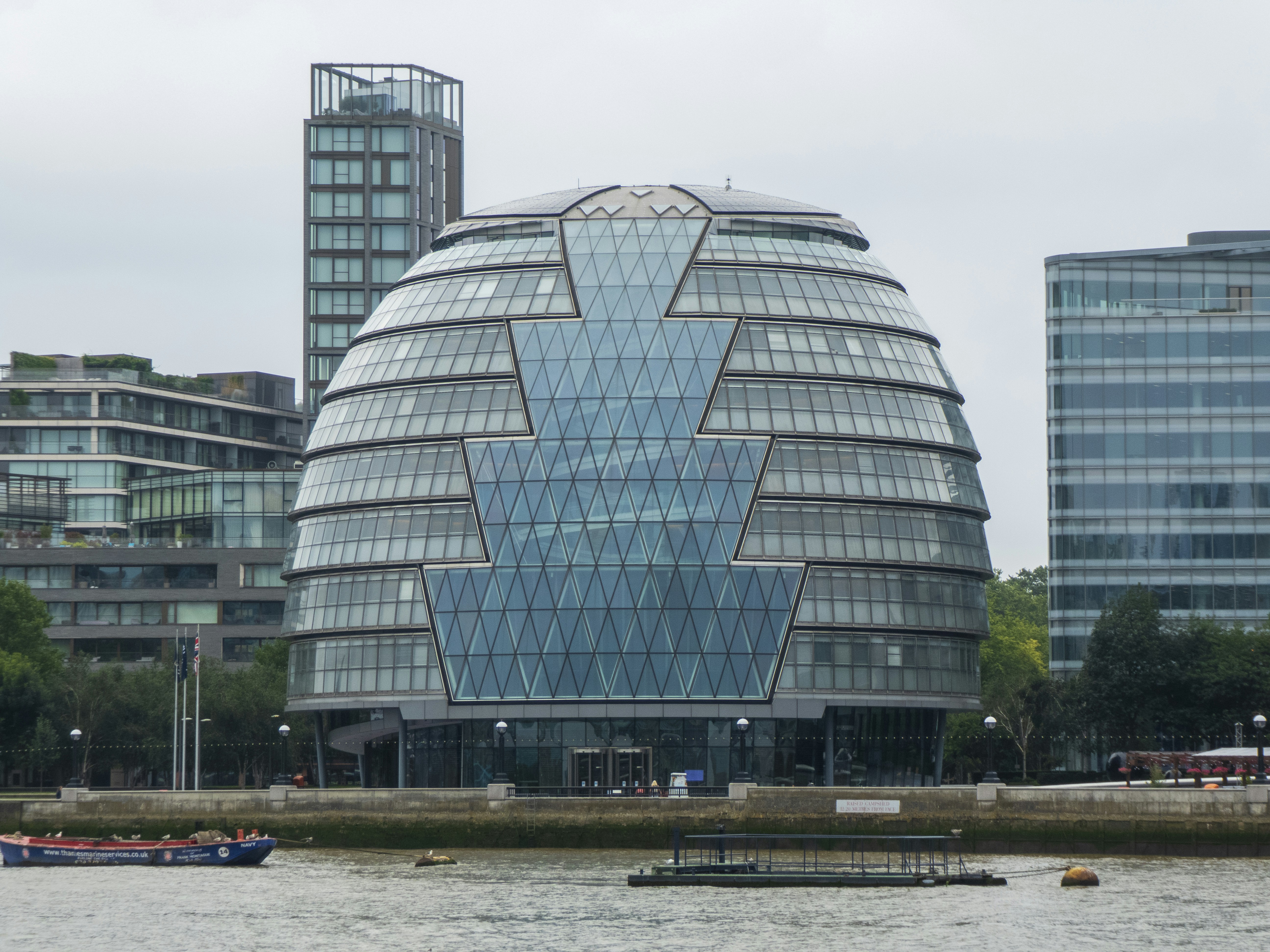 Architectural marvel featuring a glass dome with a distinctive geometric design, set against a backdrop of contemporary buildings along the river.