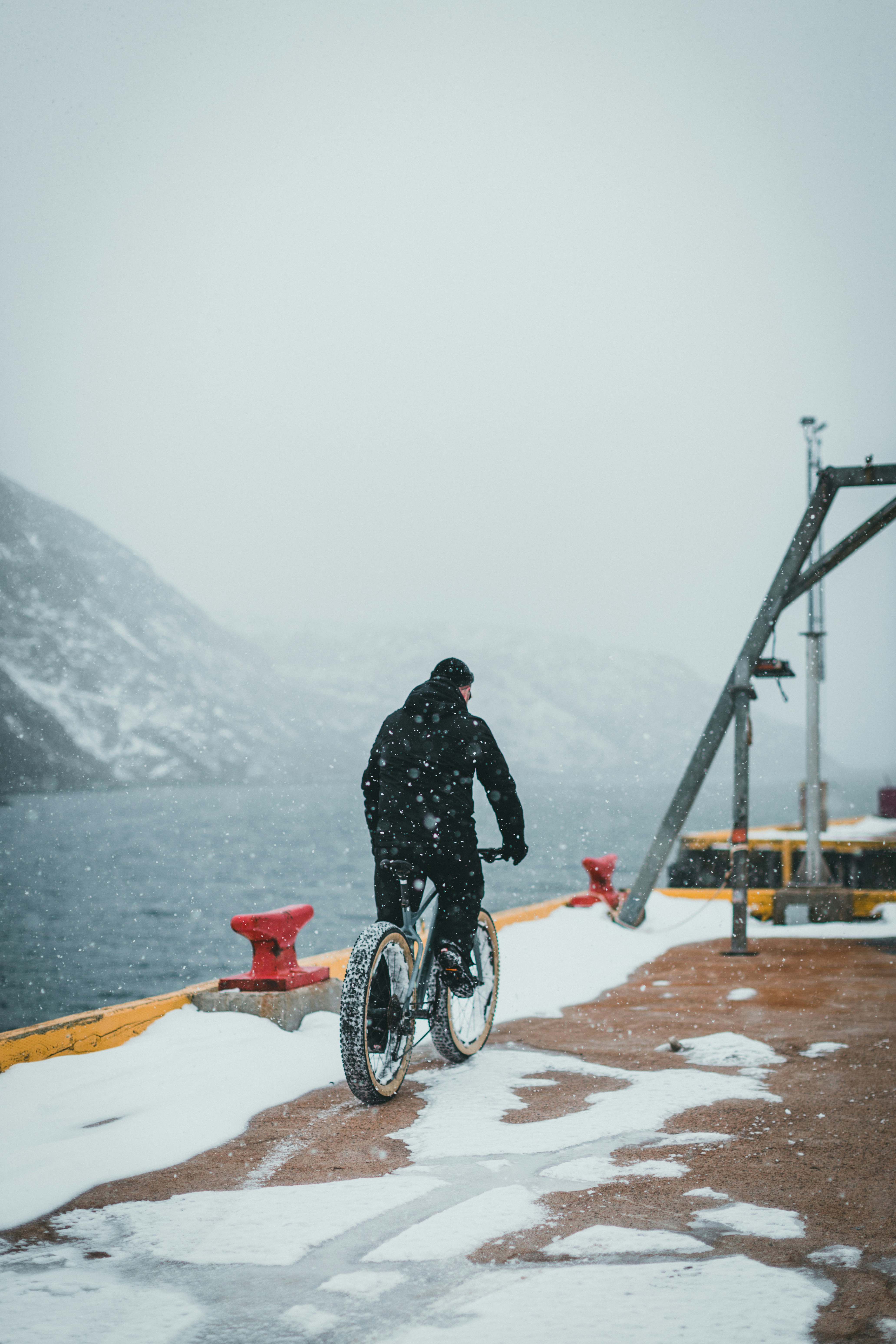 Pedestrian on a Snowy Pier: A Solitary Ride into Distant Mist