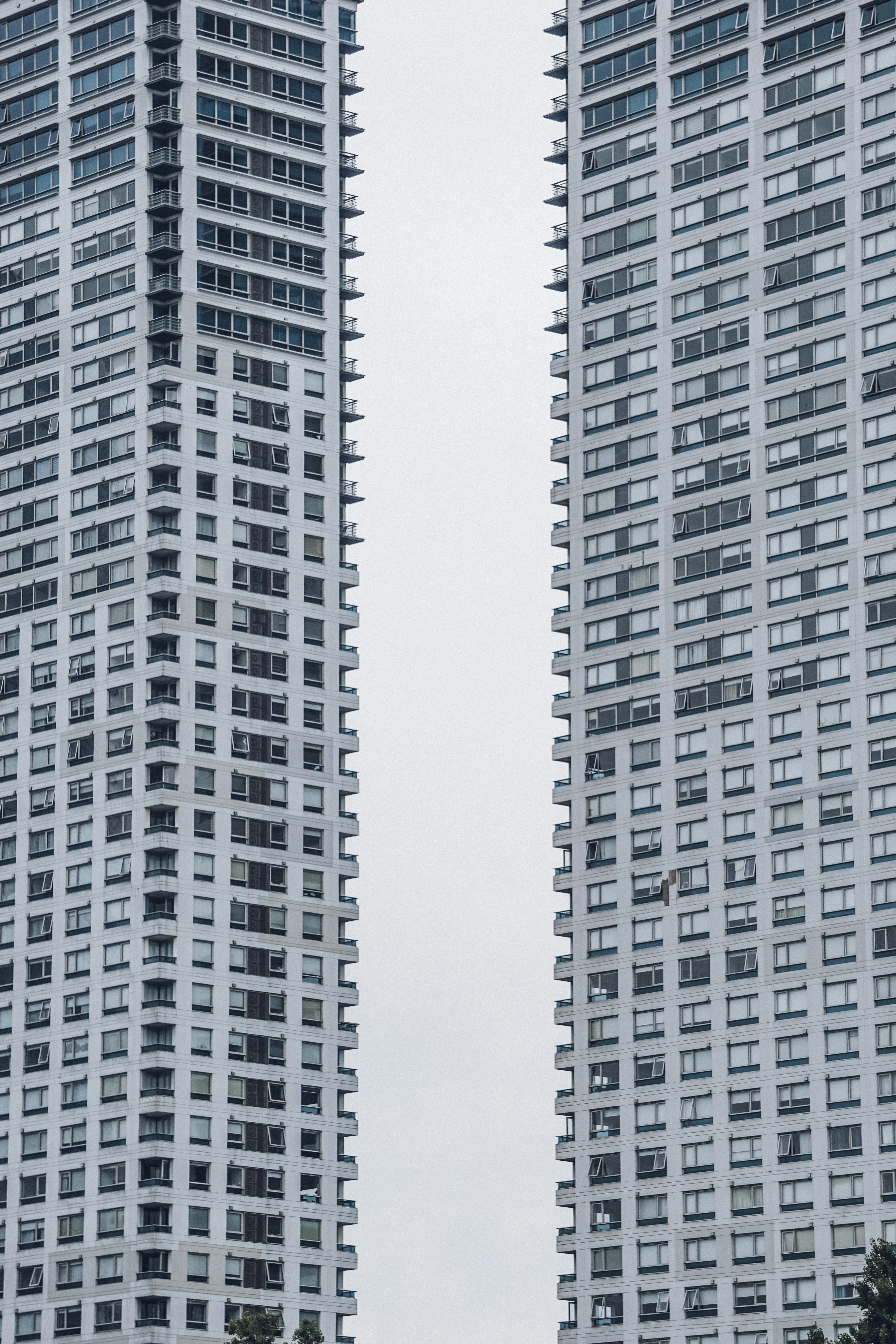 Two modern skyscrapers stand tall, creating a striking vertical symmetry against a cloudy sky.