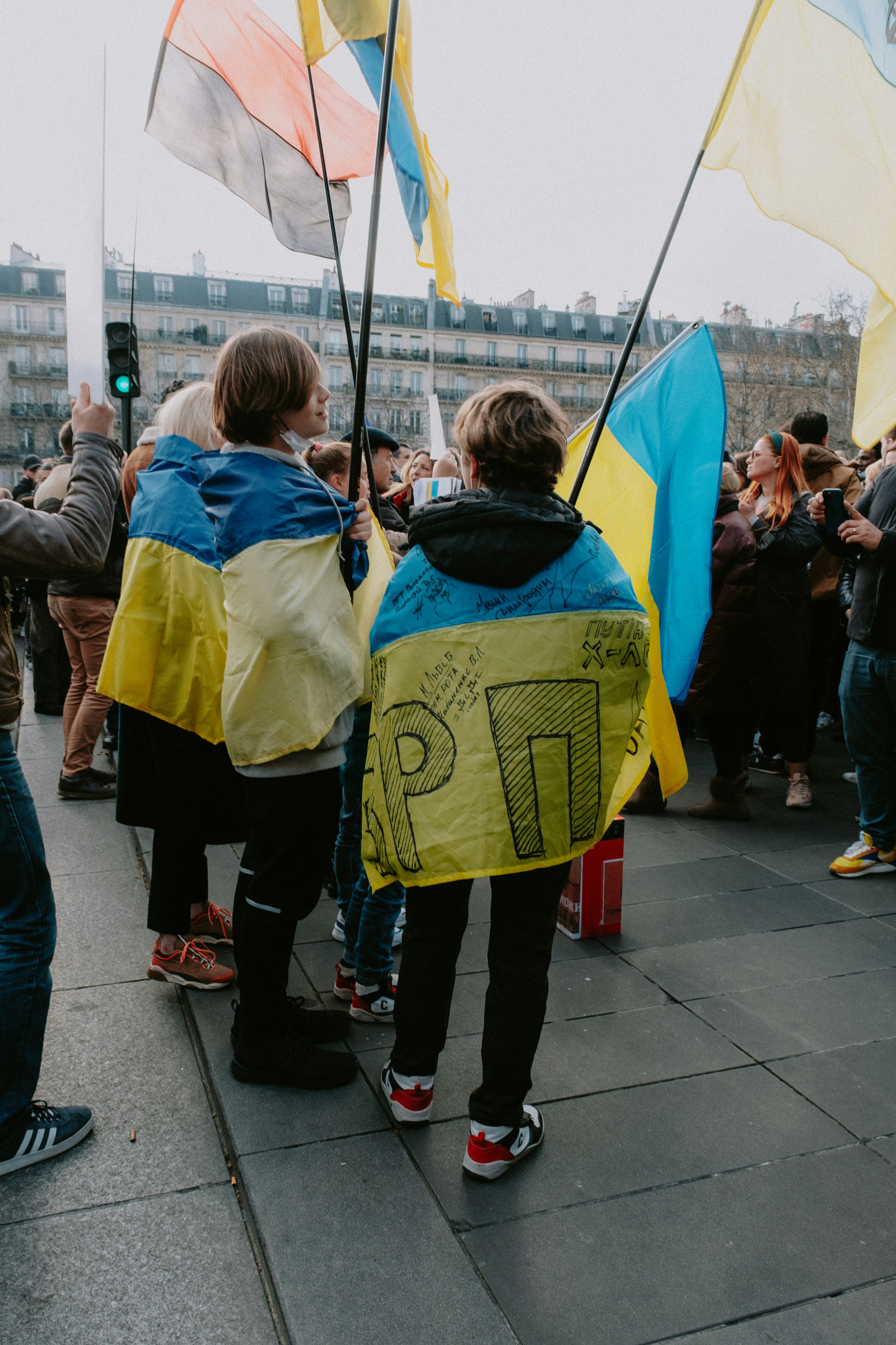 A group of people standing on a sidewalk holding flags photo – Free ...
