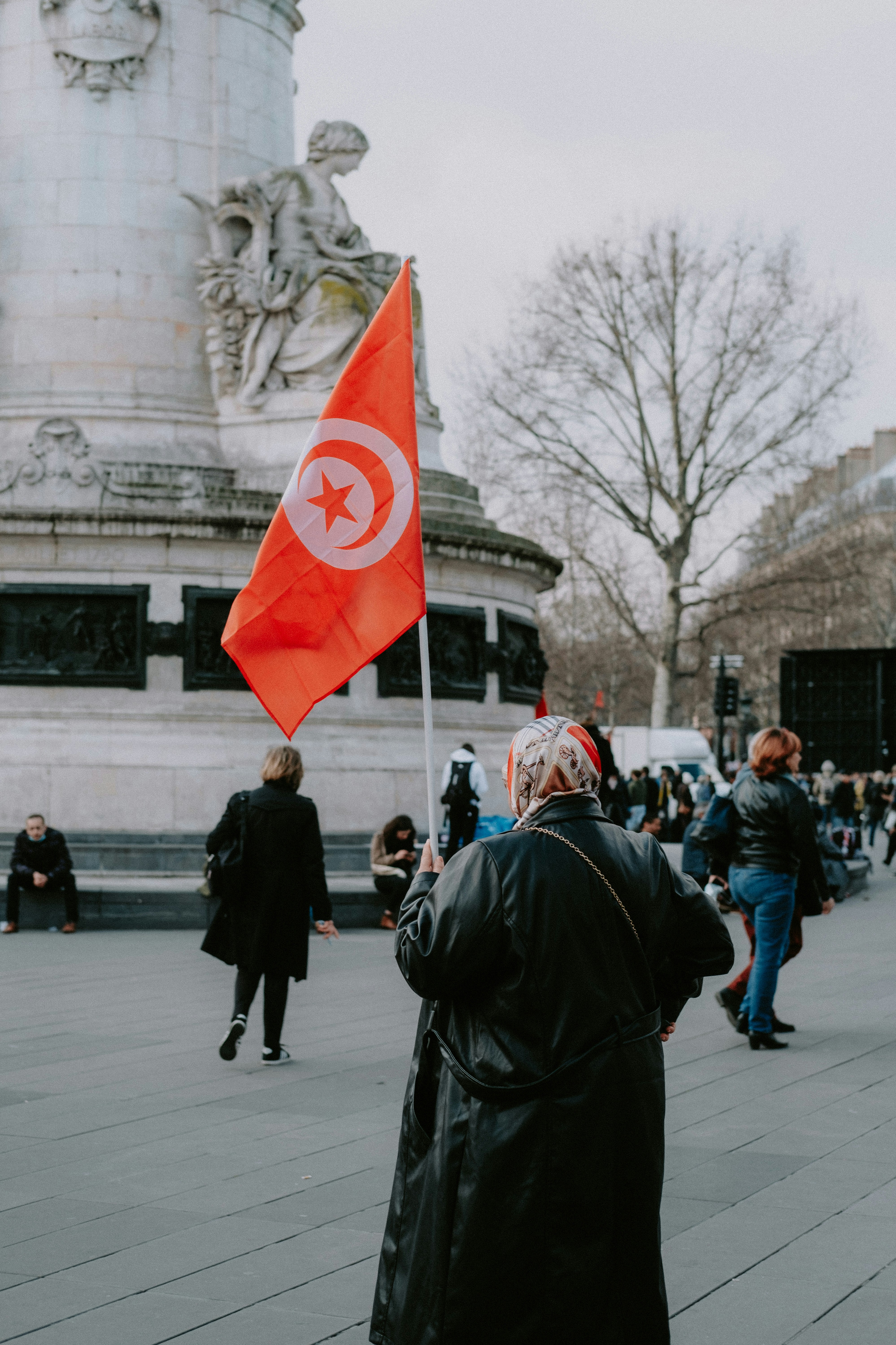 Flag Bearer by the Monument: Quiet Resolve in a City Square