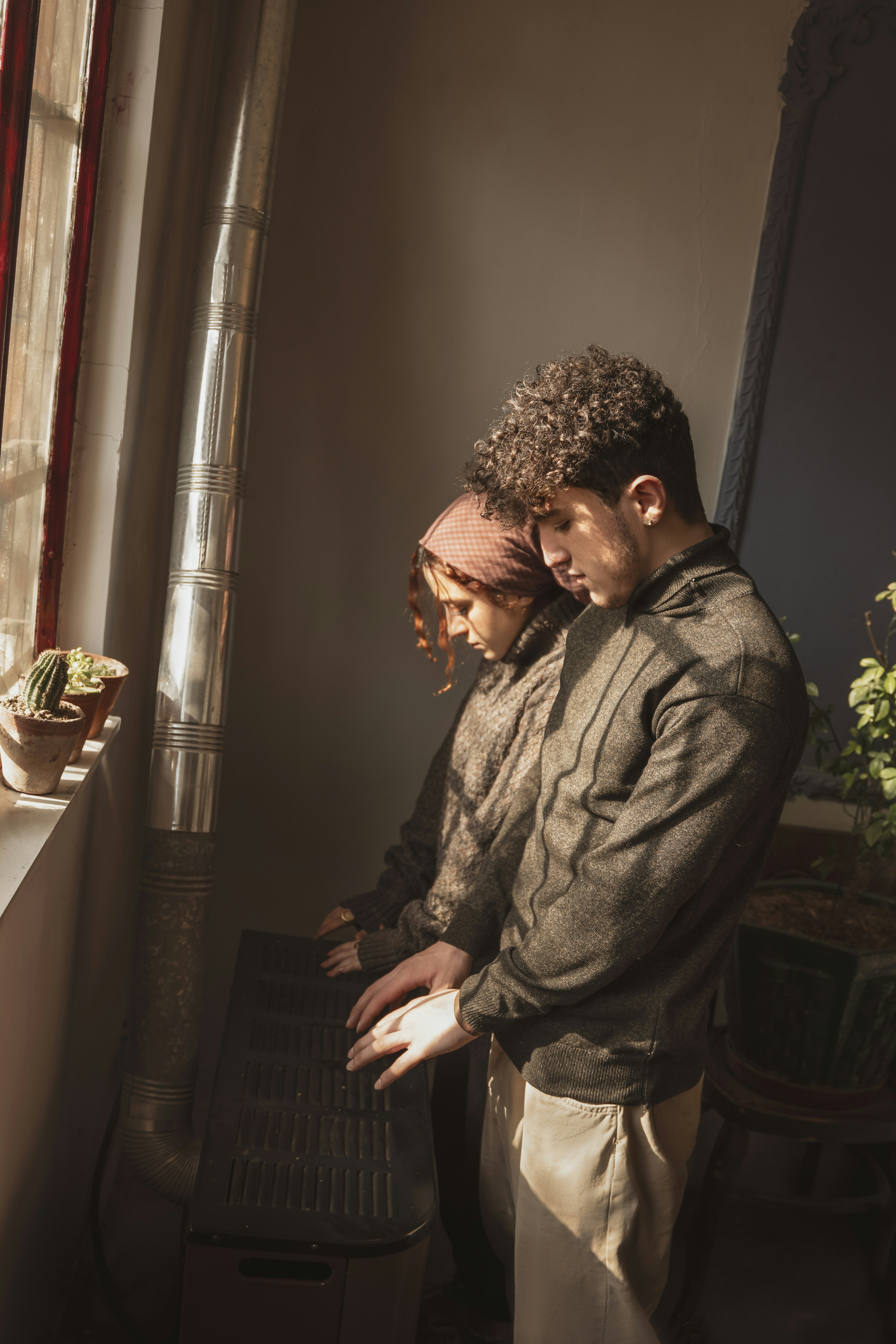 A man and a woman standing next to a window photo – Free Person Image ...