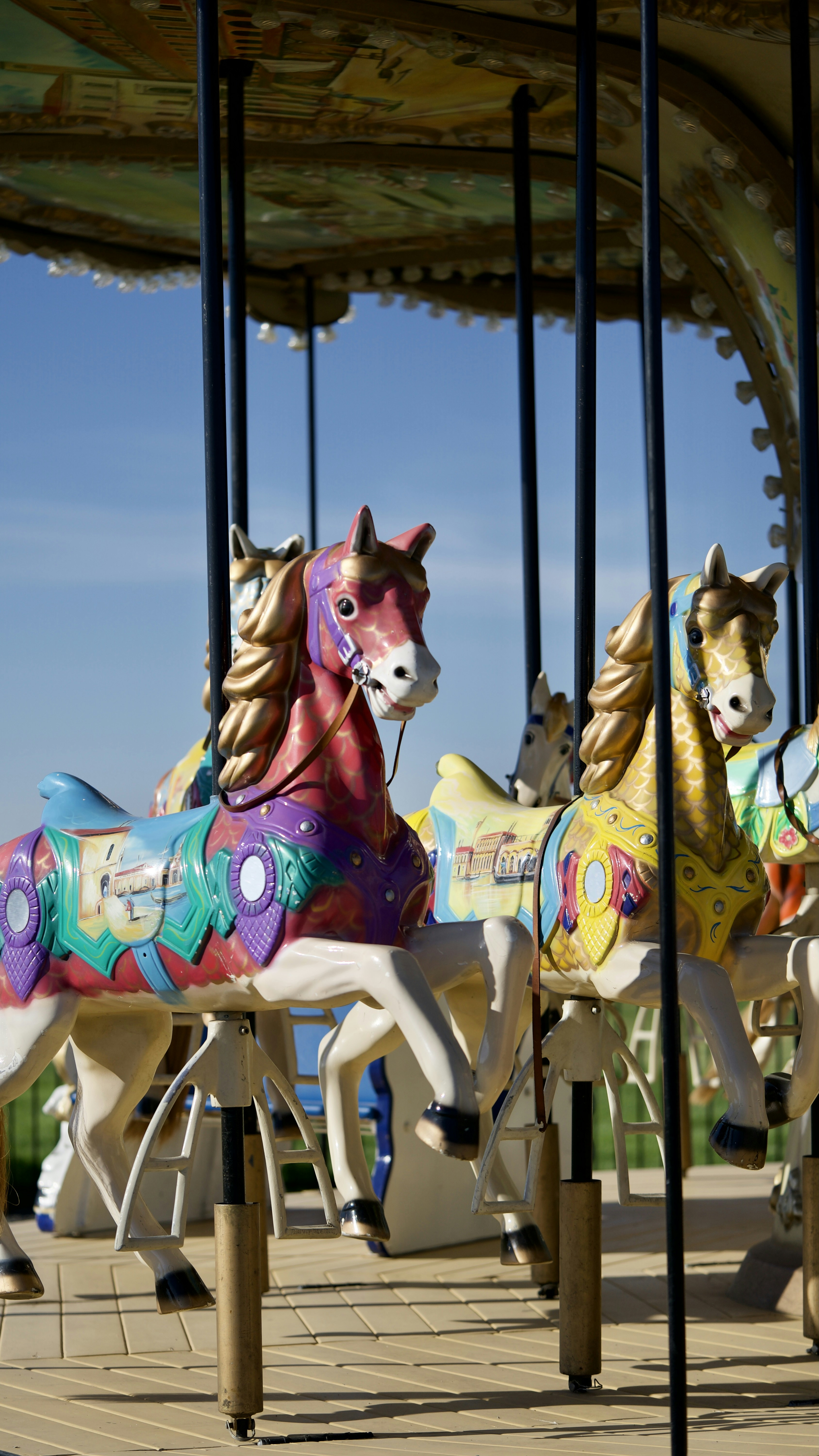 Vibrantly painted carousel horses poised for a joyful ride, set against a clear blue sky.
