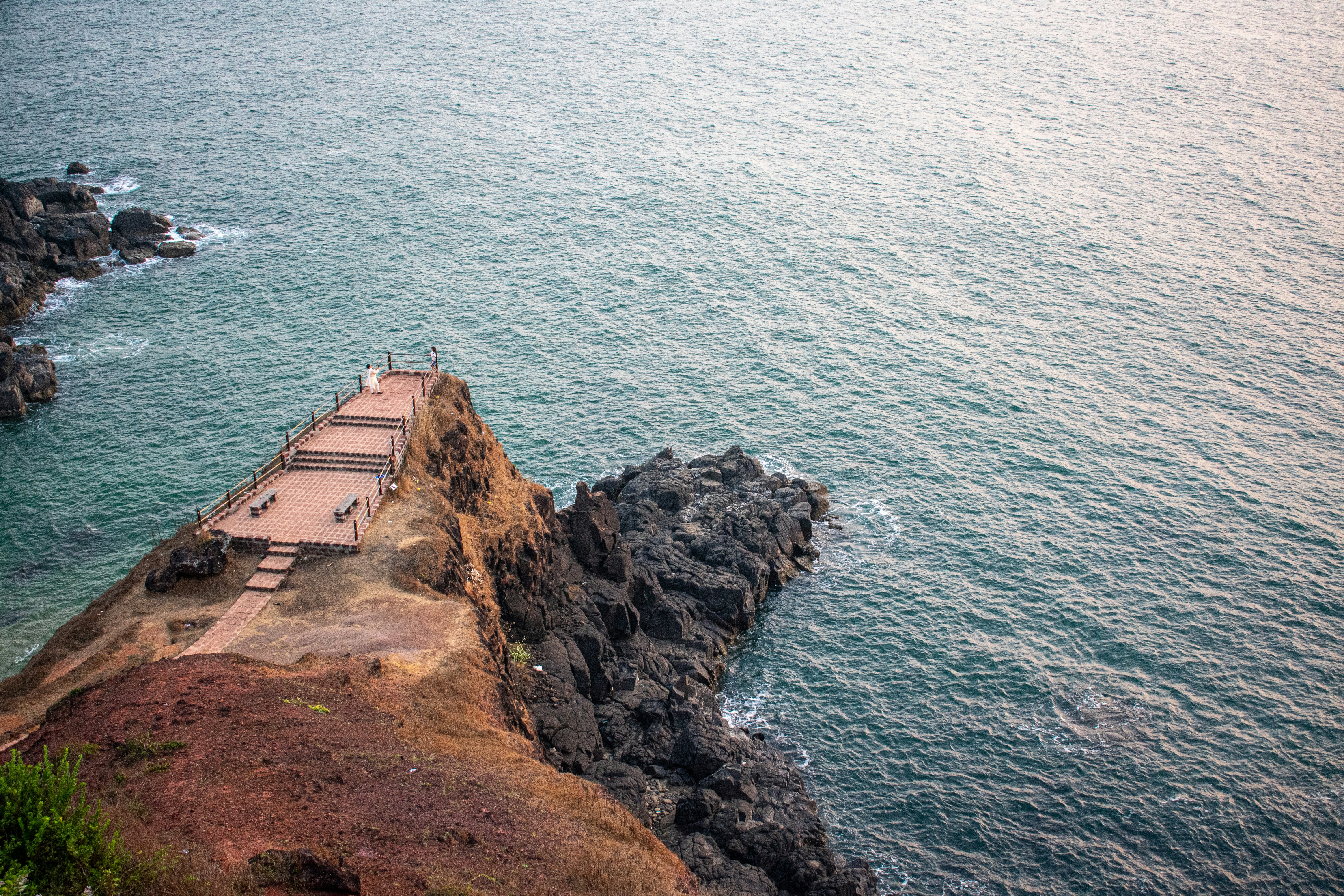 A pier sitting on top of a cliff next to the ocean photo – Free Land ...