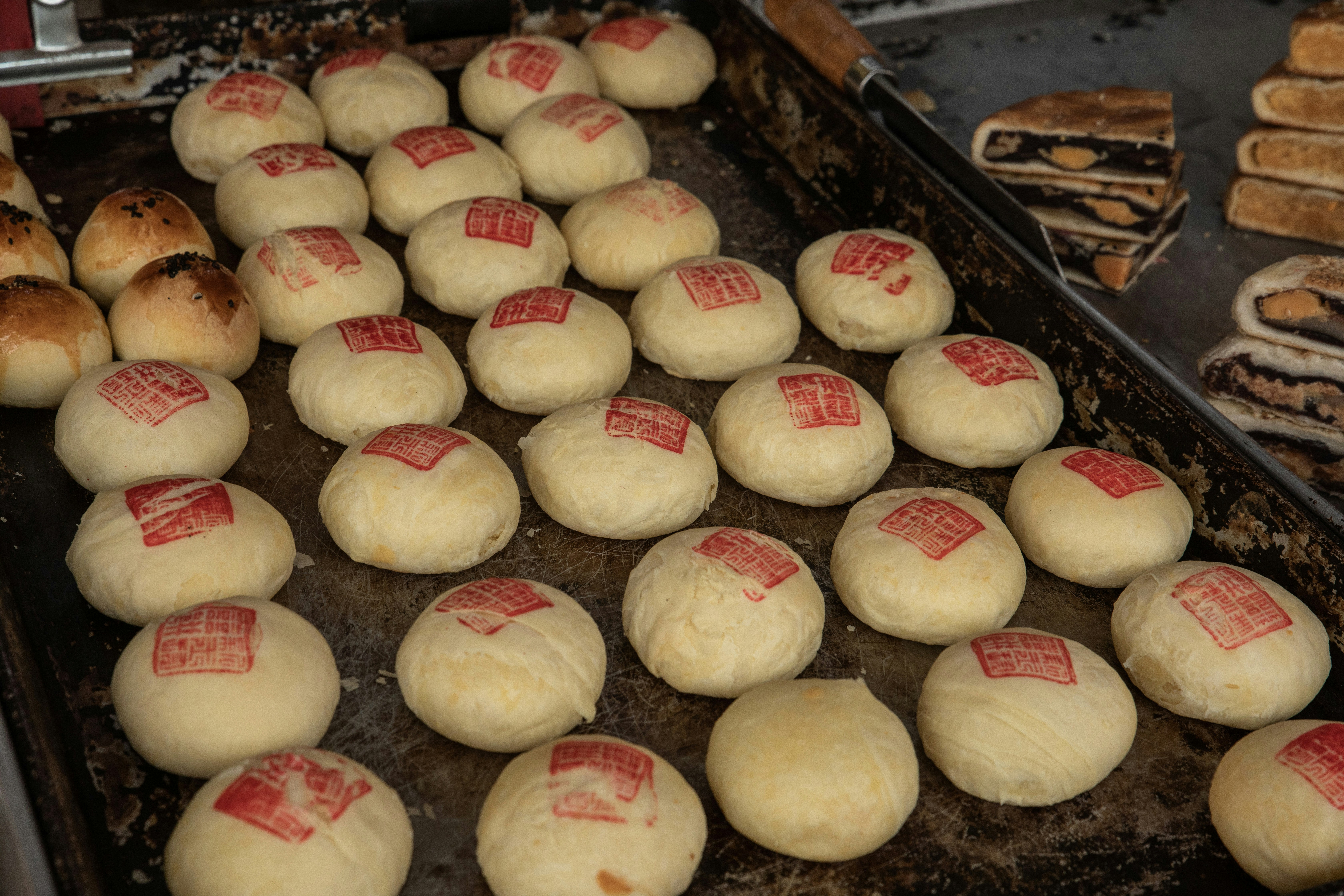 Batch of stamped doughy buns cooling on a baking sheet