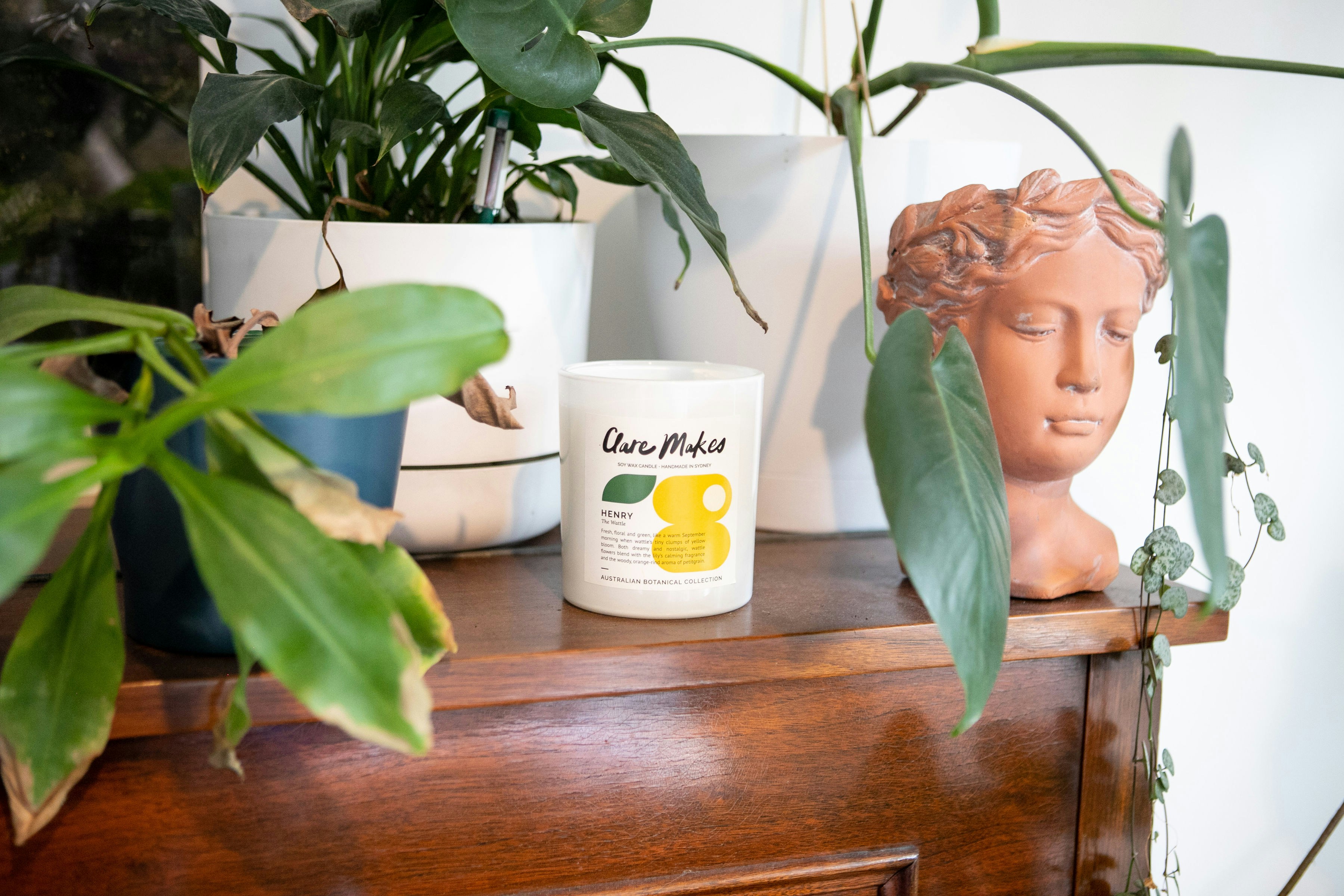 Ceramic bust watches over a candle-filled green corner