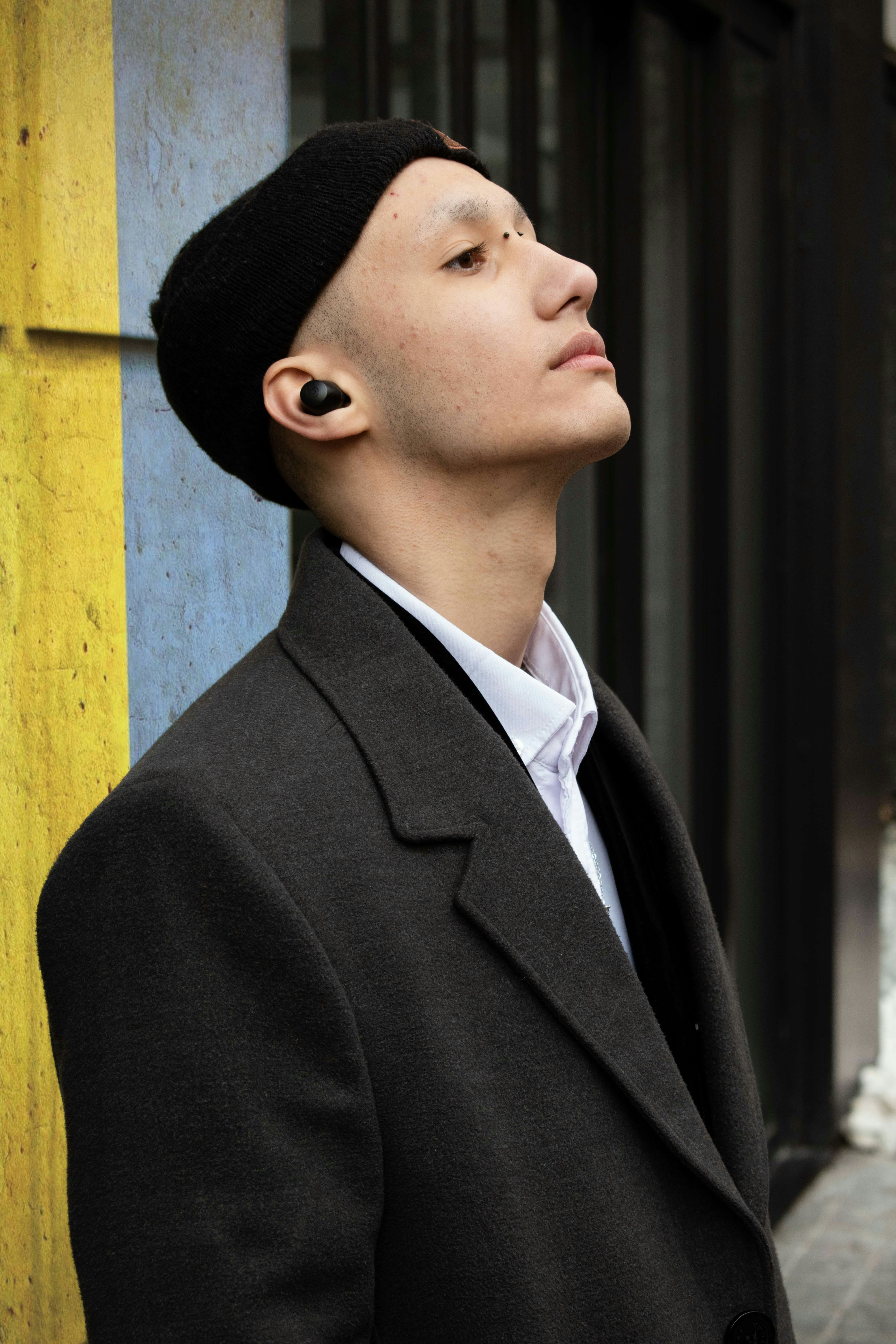 A man with ear buds standing in front of a building photo – Free Woman ...
