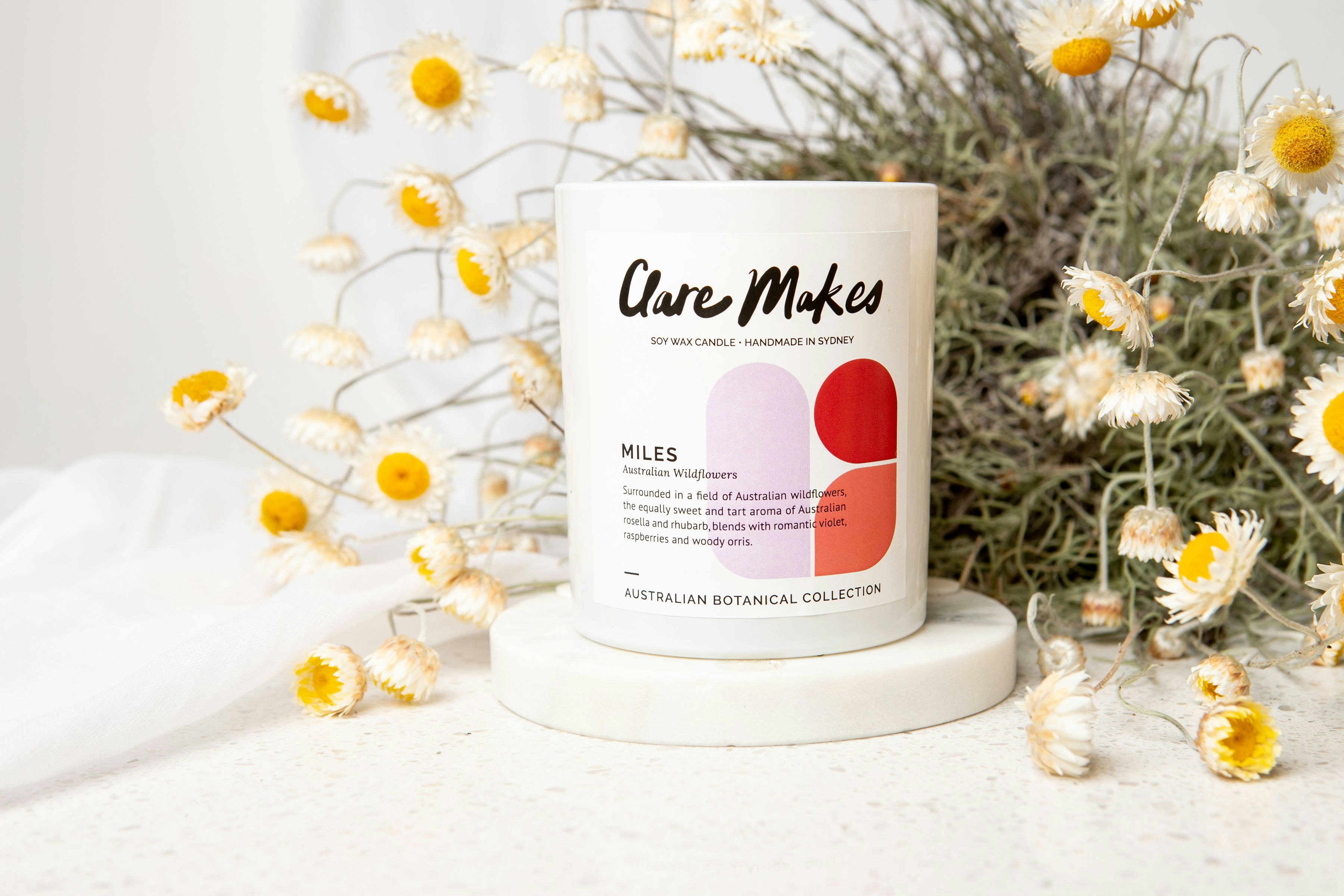 Botanical Candle Centered on Marble Pedestal Amid Daisy Harvest
