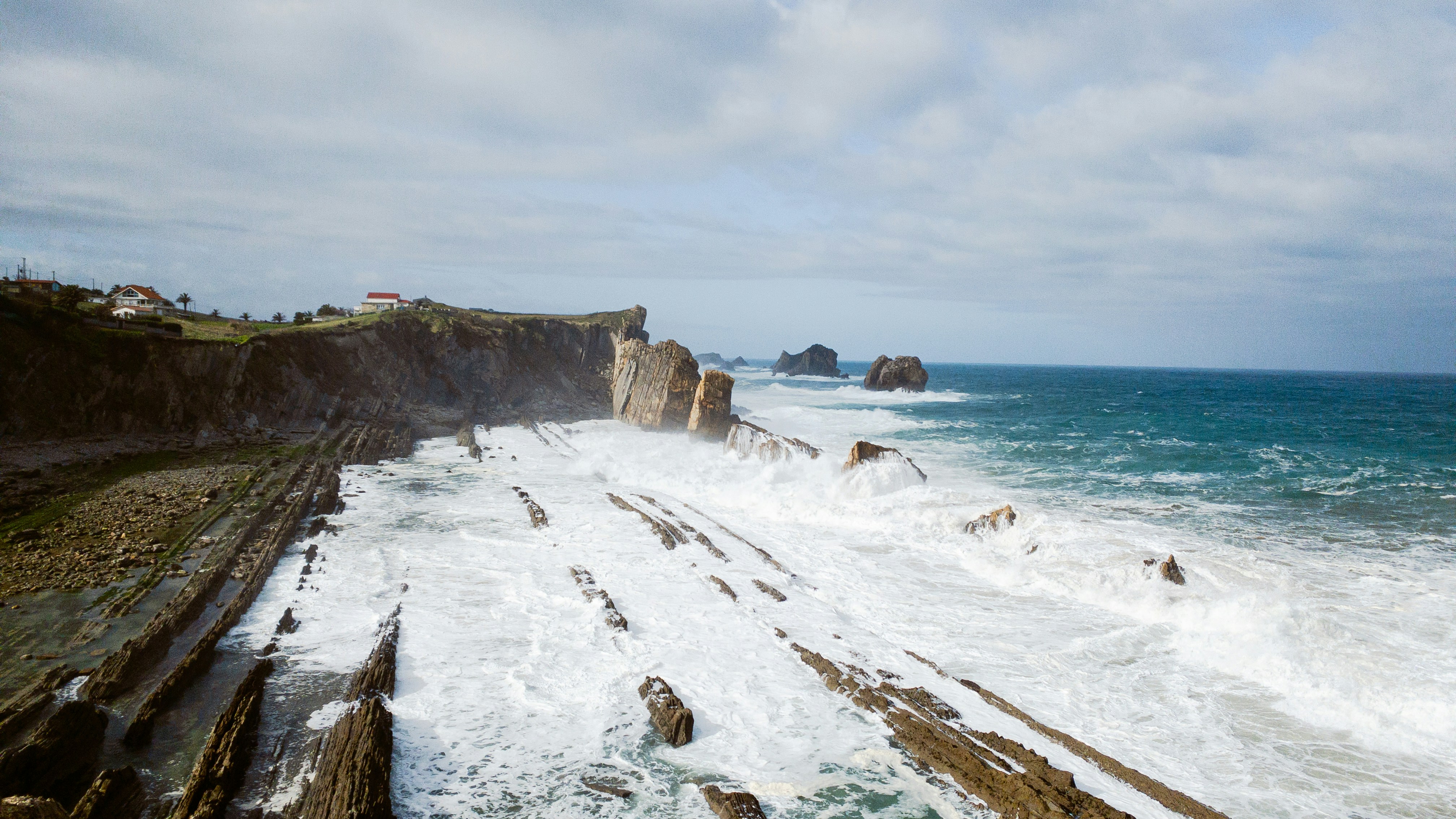 Striated Coastline: Foam, Rock Strata, and Coastal Homes