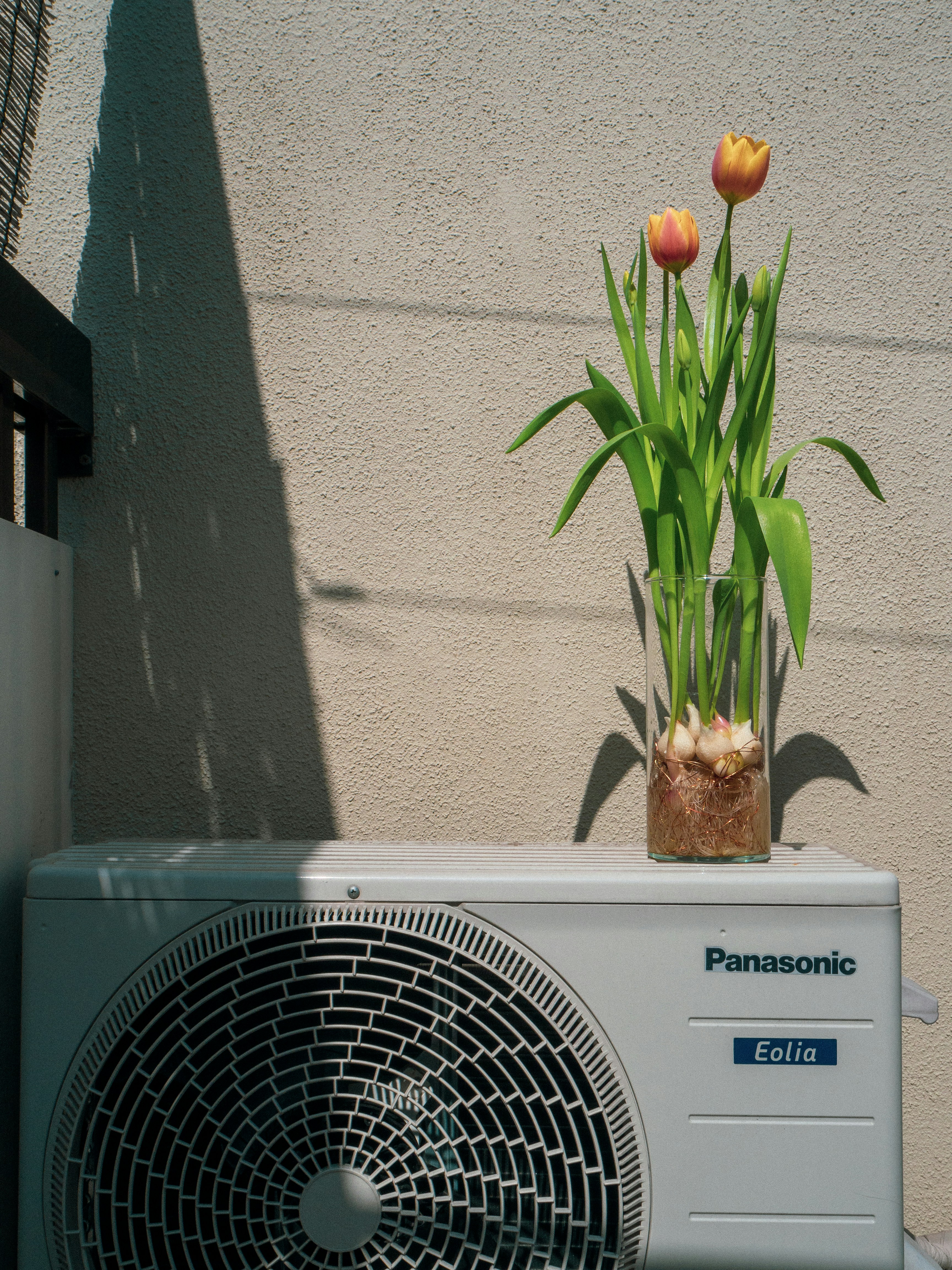 A small air conditioner sitting next to a flower pot photo – Free ...