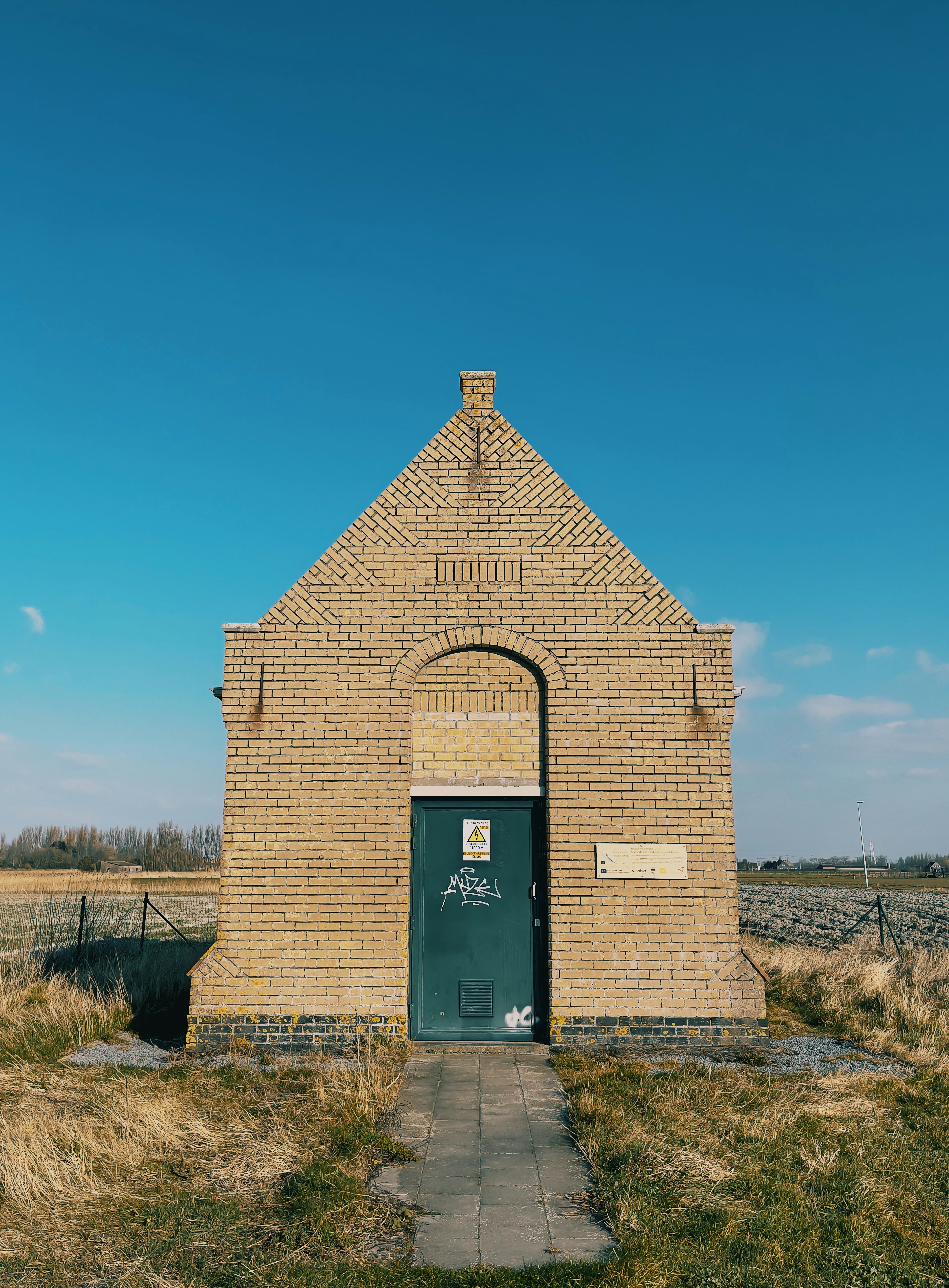 Doorway at the Edge of Fields: A Brick Chapel Under a Wide Sky