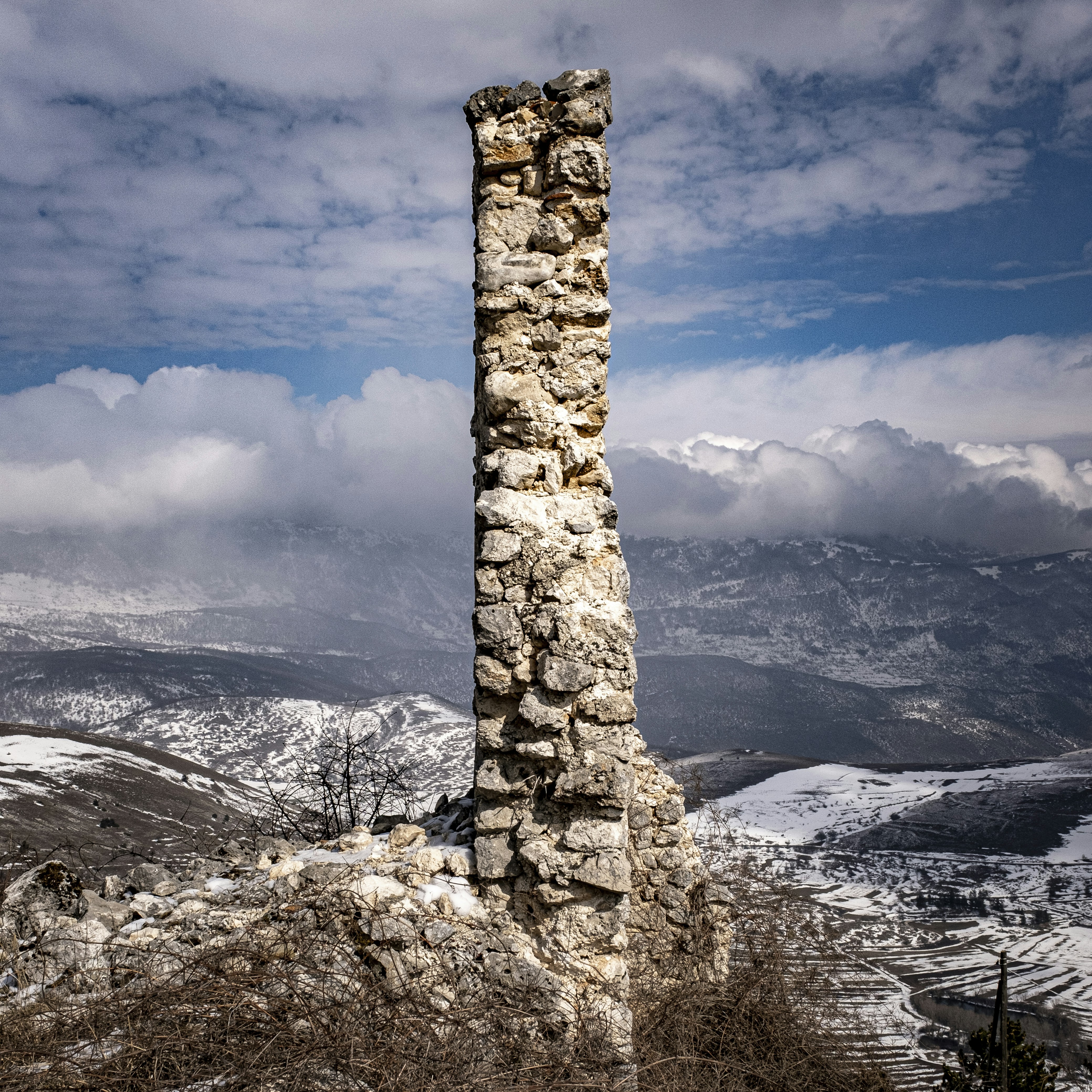 a tall stone tower sitting on top of a snow covered hillside