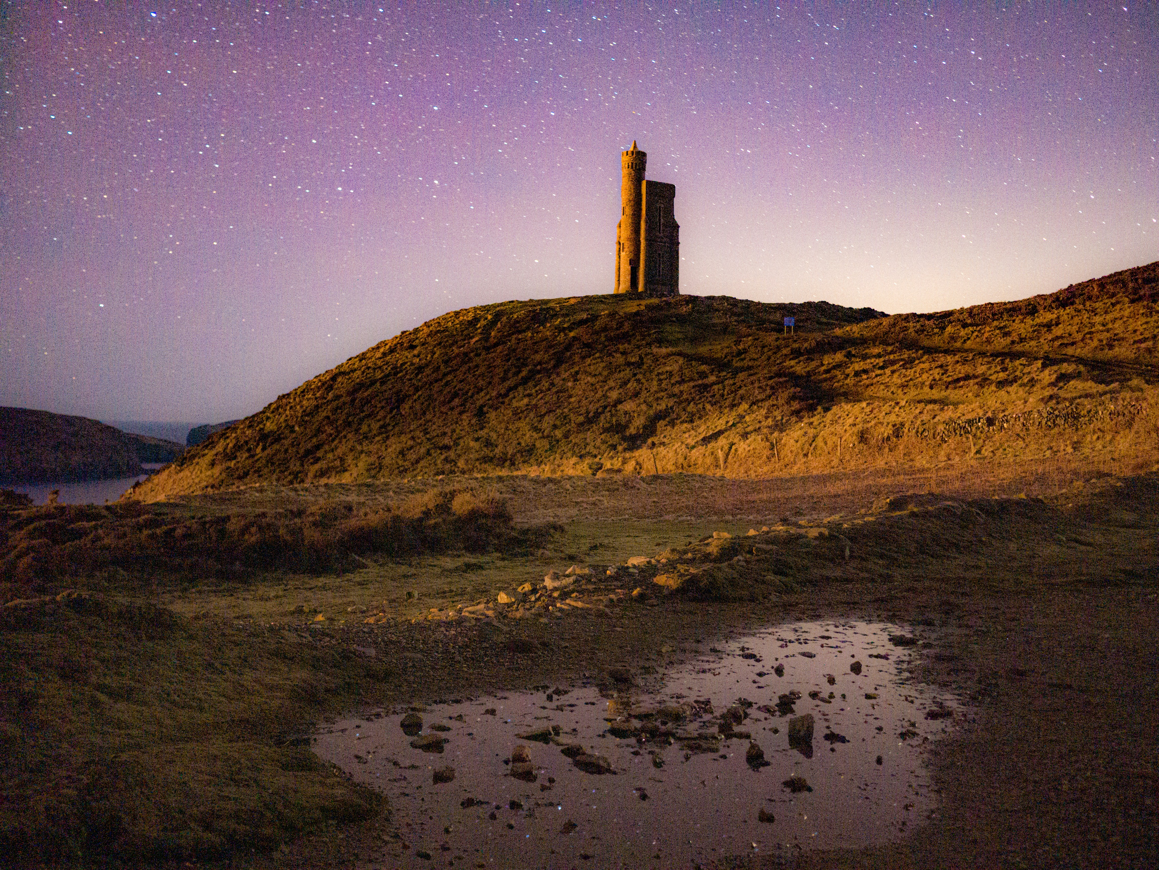 Starry Night Over a Lone Coastal Keep on a Wind-Swept Hill