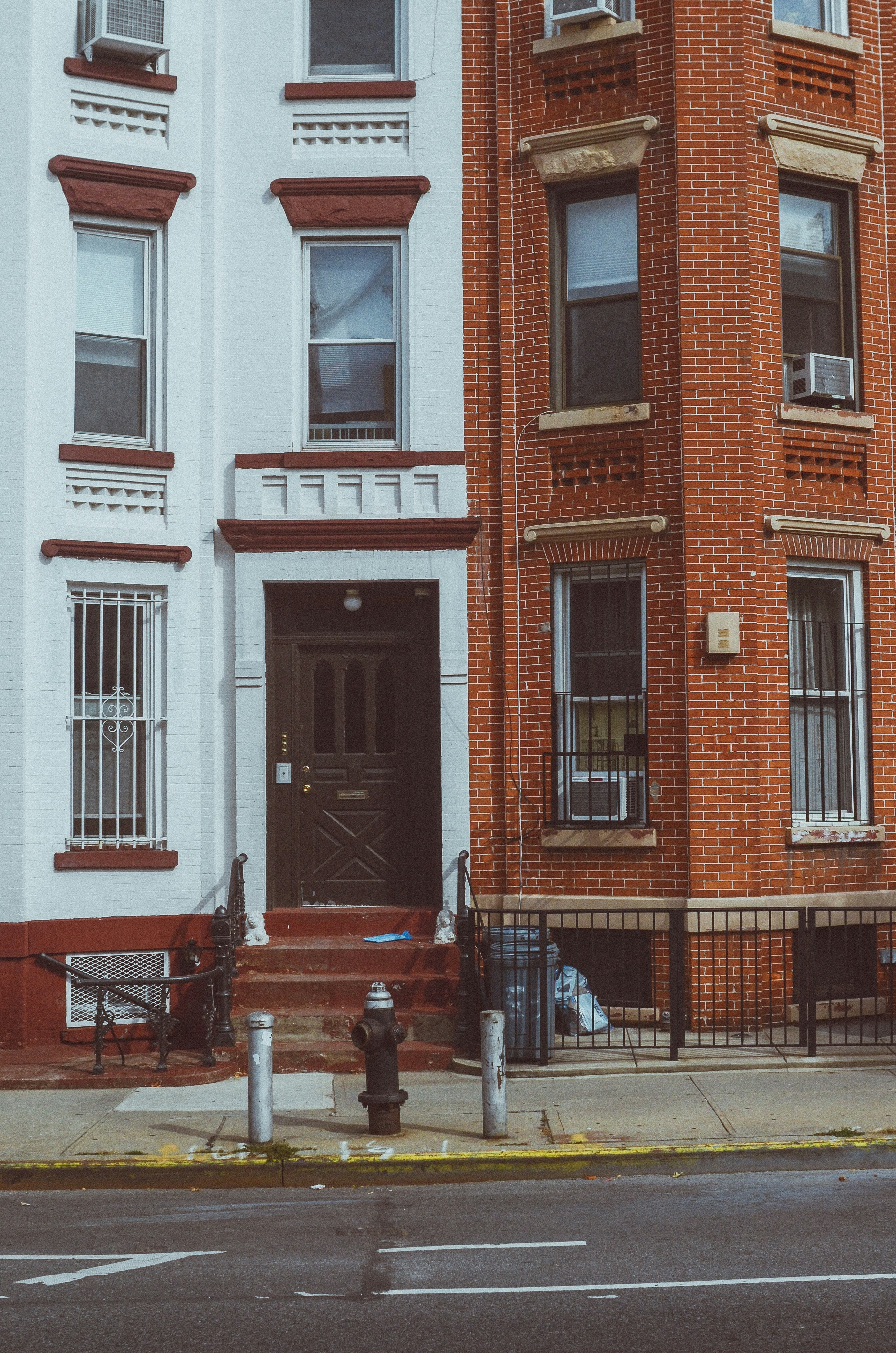 Architectural juxtaposition of a white and red brick building, showcasing intricate details and urban life elements.