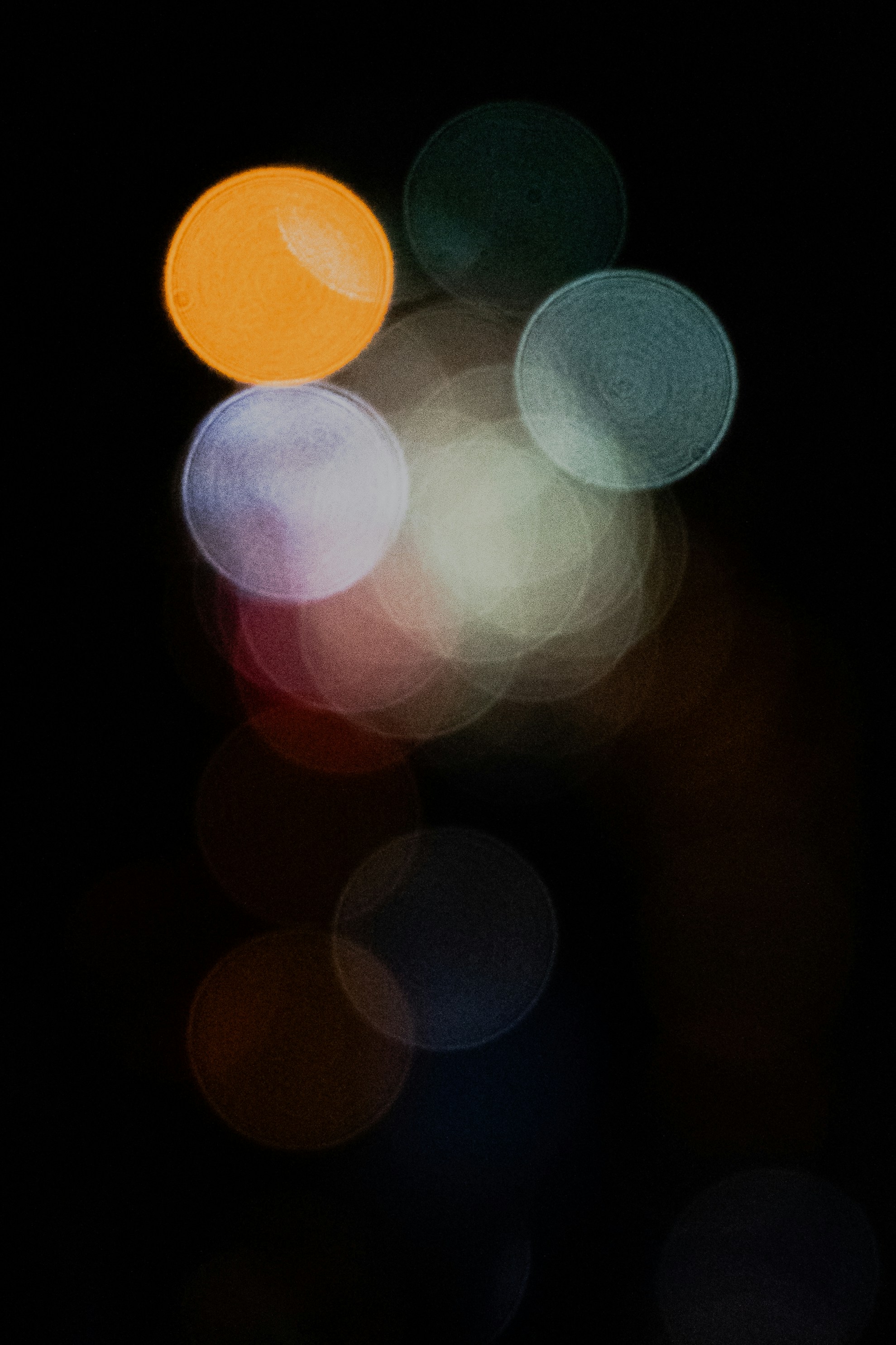 Abstract bokeh composition featuring vibrant orbs of color against a dark background. The interplay of light creates a dreamy visual effect.