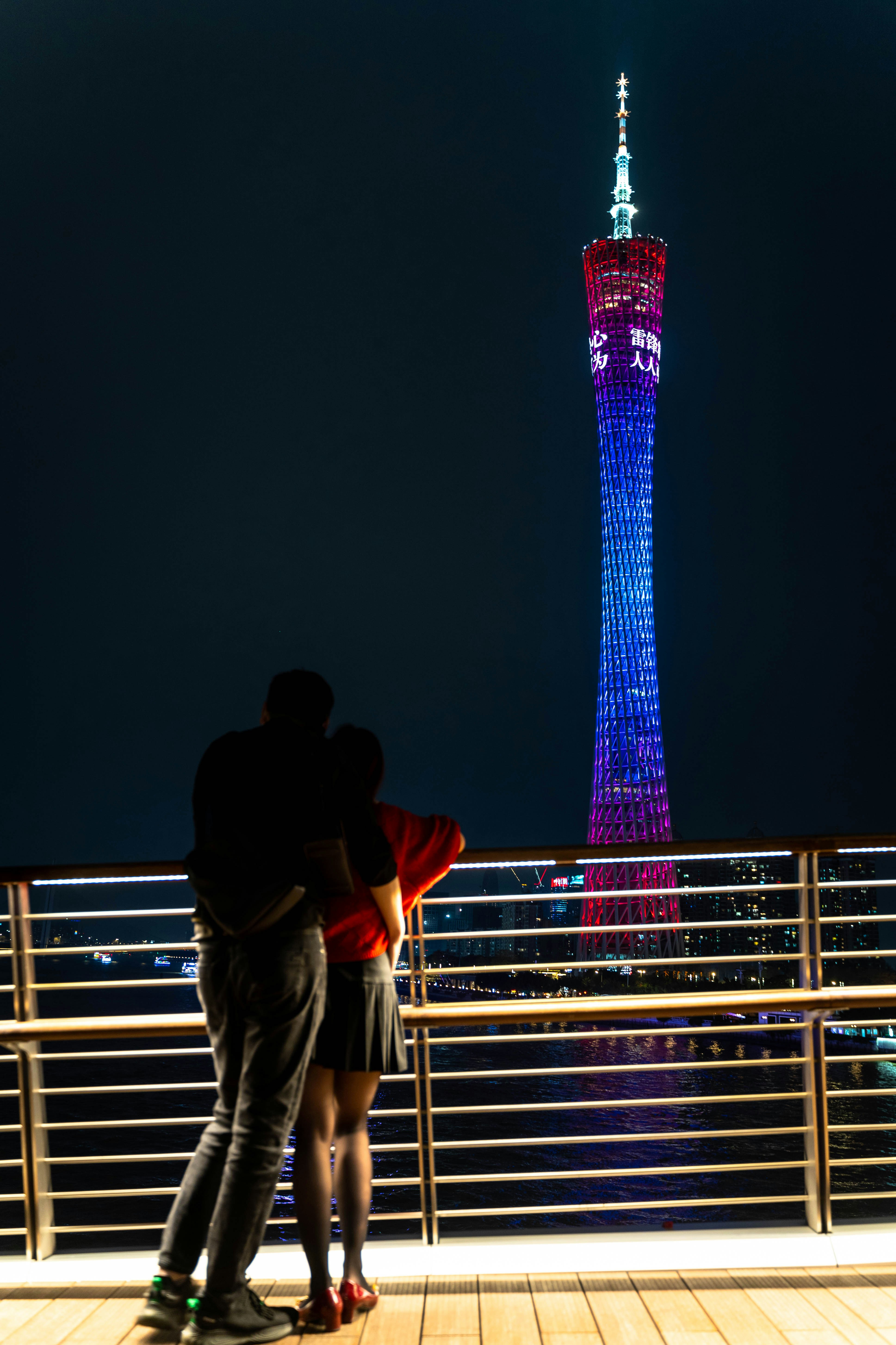 a man and a woman standing next to each other in front of a tall tower