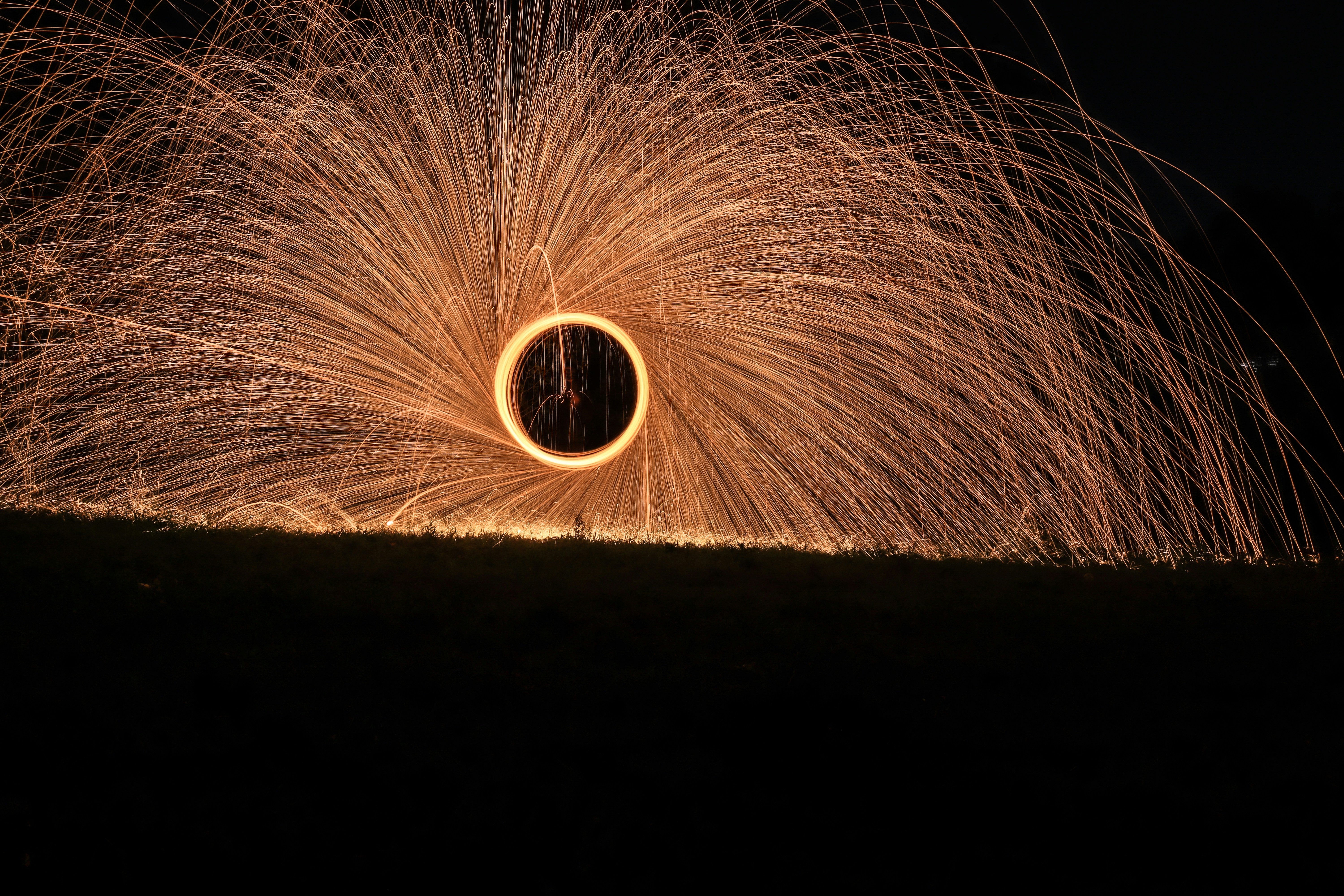Circular pattern of glowing sparks emanating from a central point, creating a mesmerizing display against a dark background.