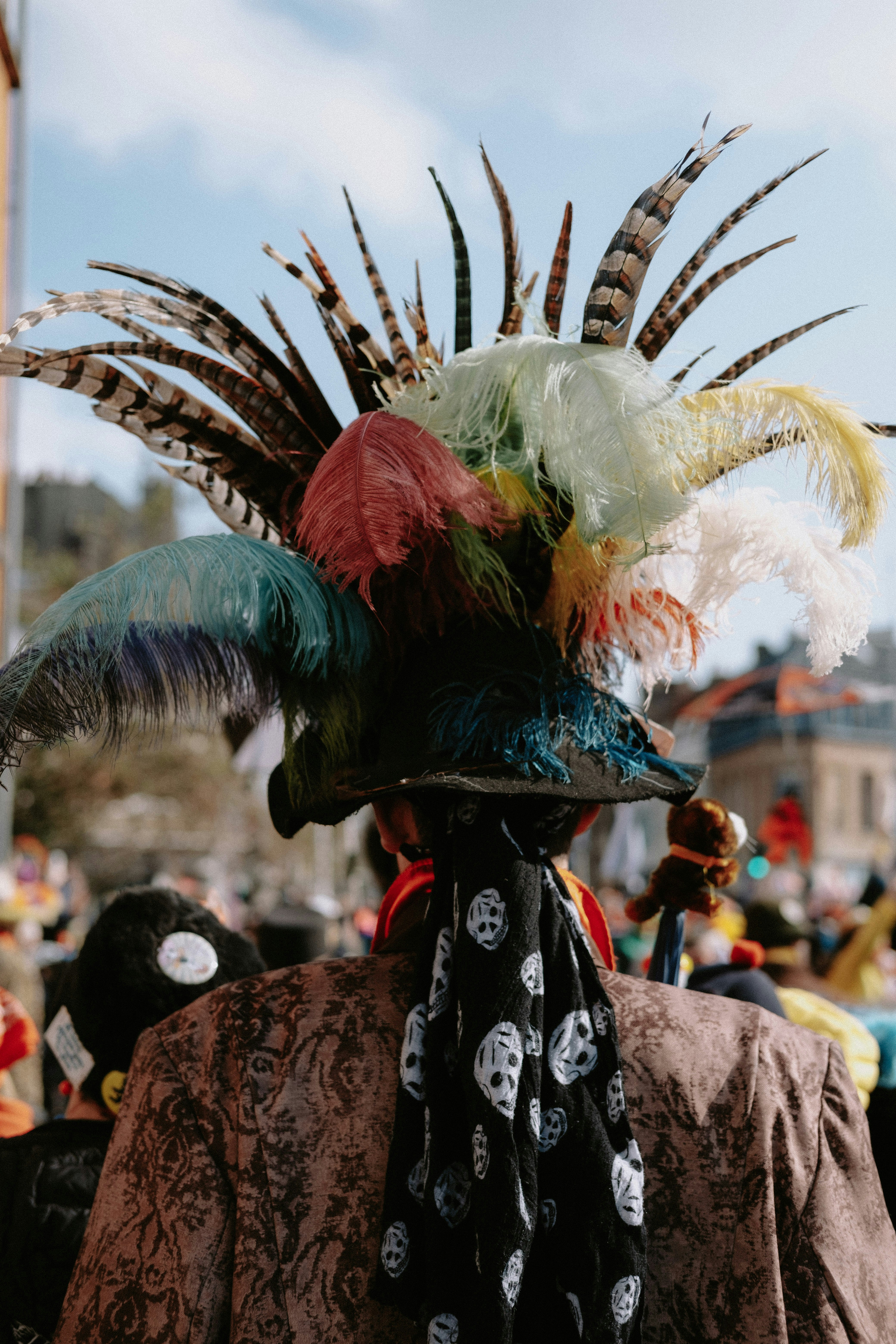 Vibrant feathers adorn a traditional hat, worn by a participant in a festive gathering, highlighting cultural heritage and artistry.