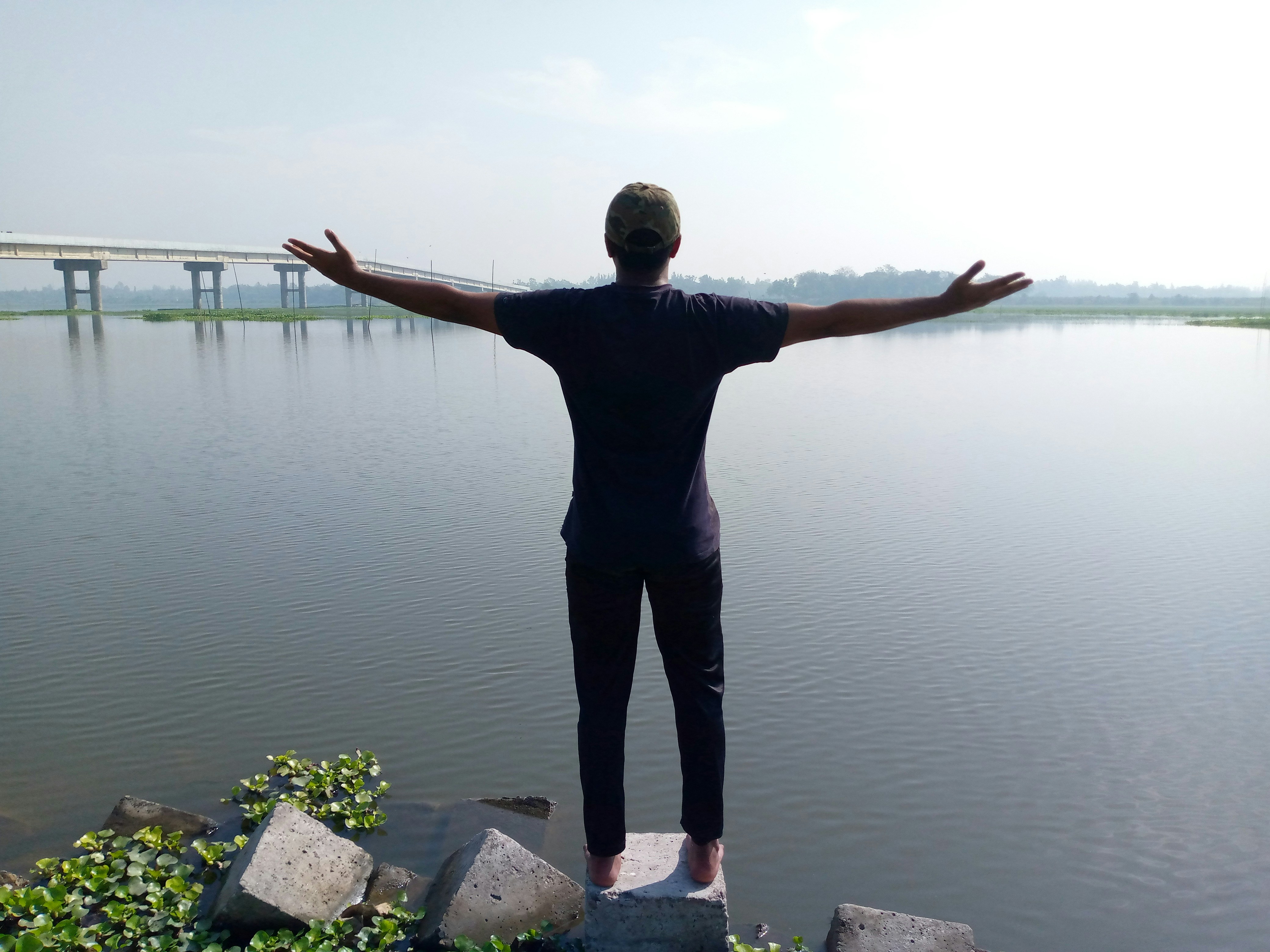 Threshold of Calm: A Solitary Figure Arms-Wide Over the Quiet River
