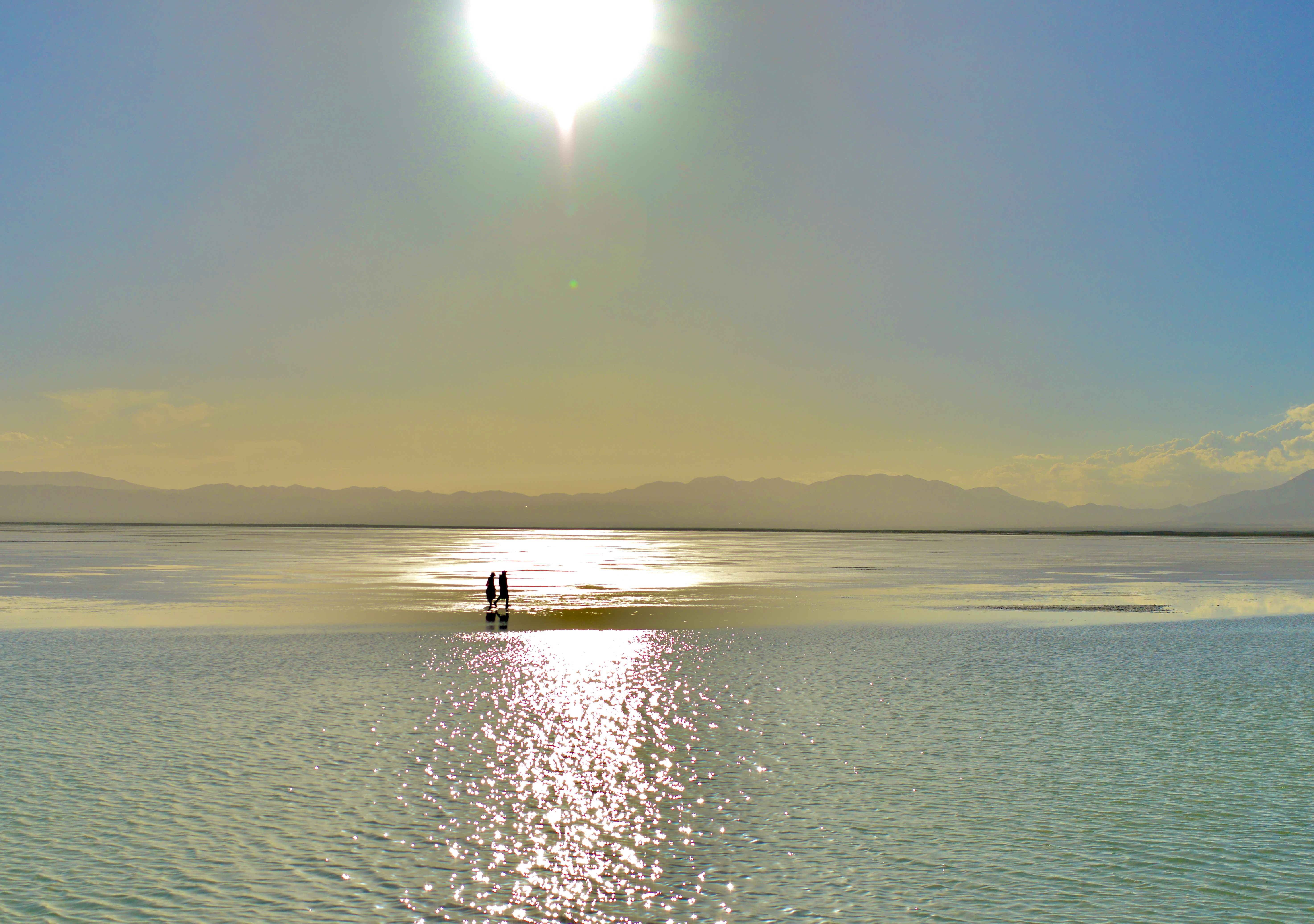 A couple of people standing on top of a large body of water photo ...
